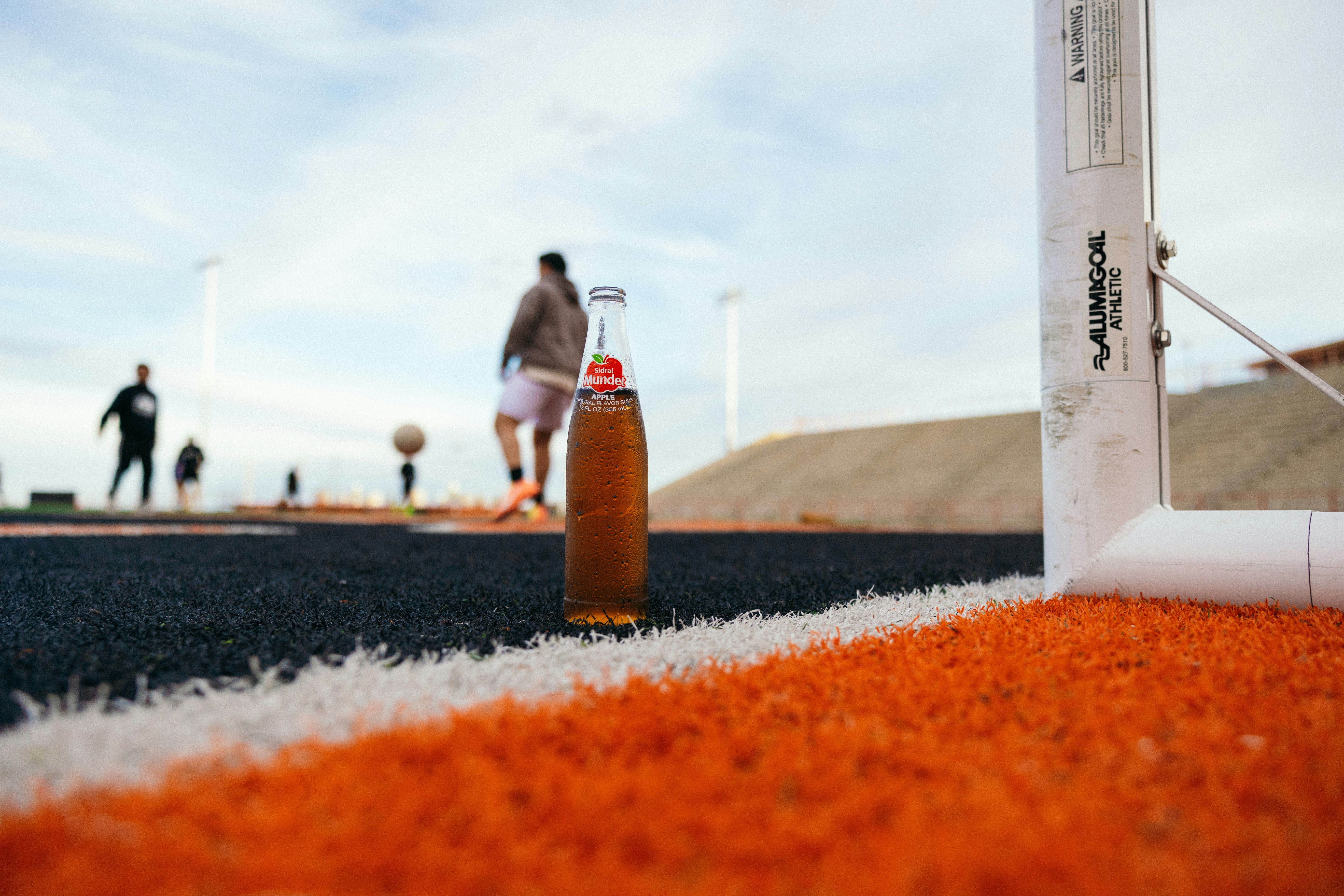 Amber Bottle on the Painted Line: A Quiet Moment at the Field Edge