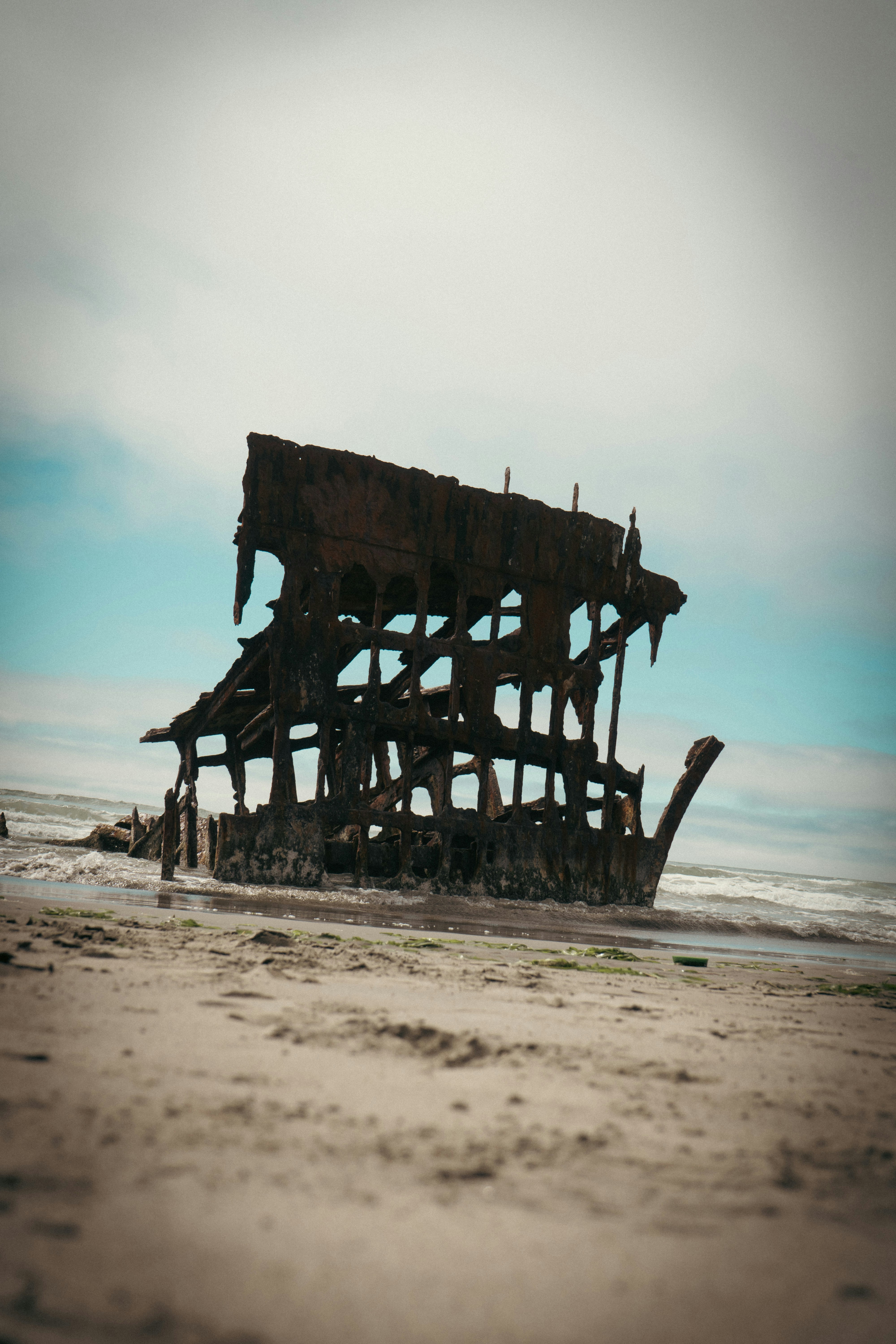 a rusted ship sitting on top of a sandy beach