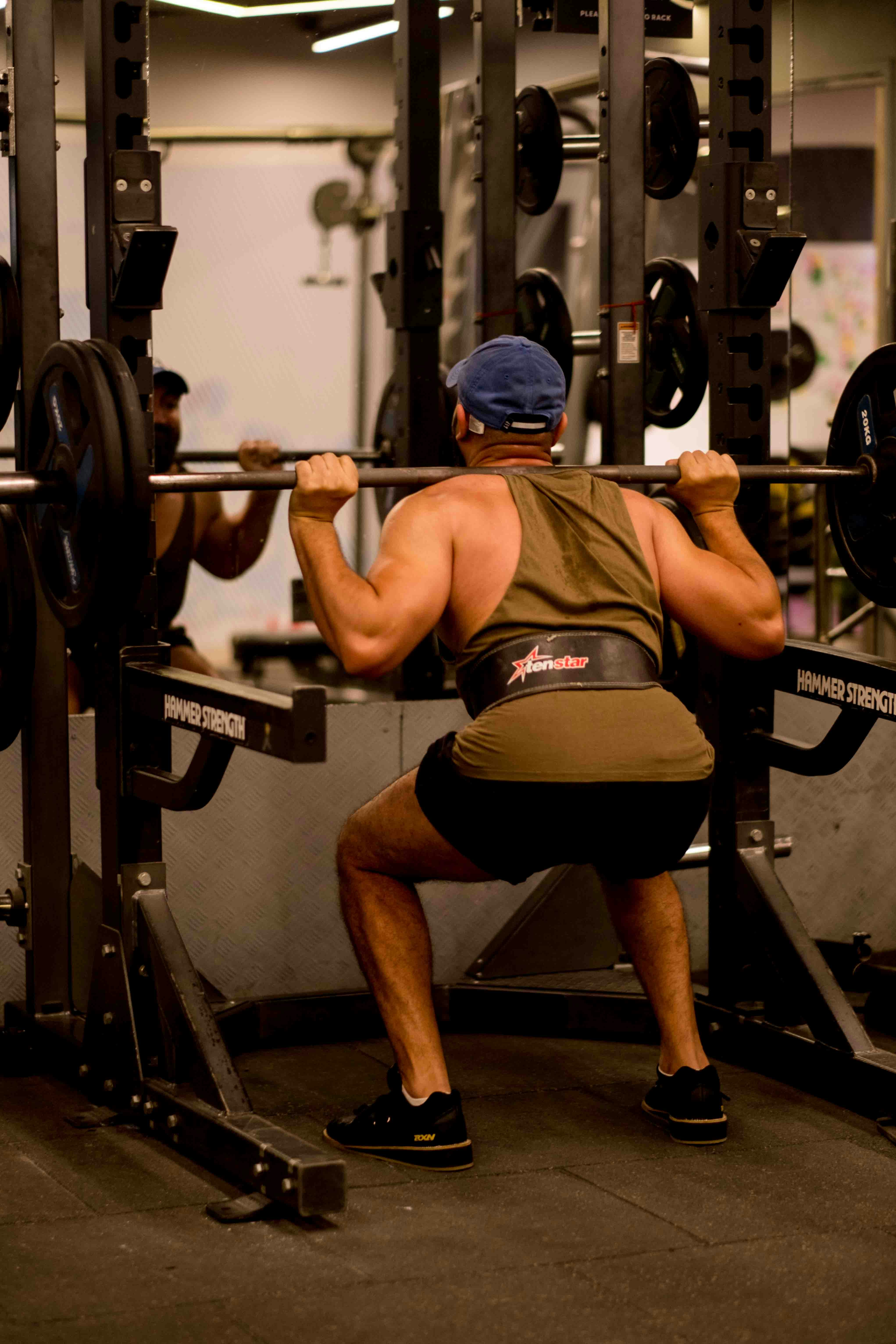 A man squats in front of a barbell photo – Free Man Image on Unsplash