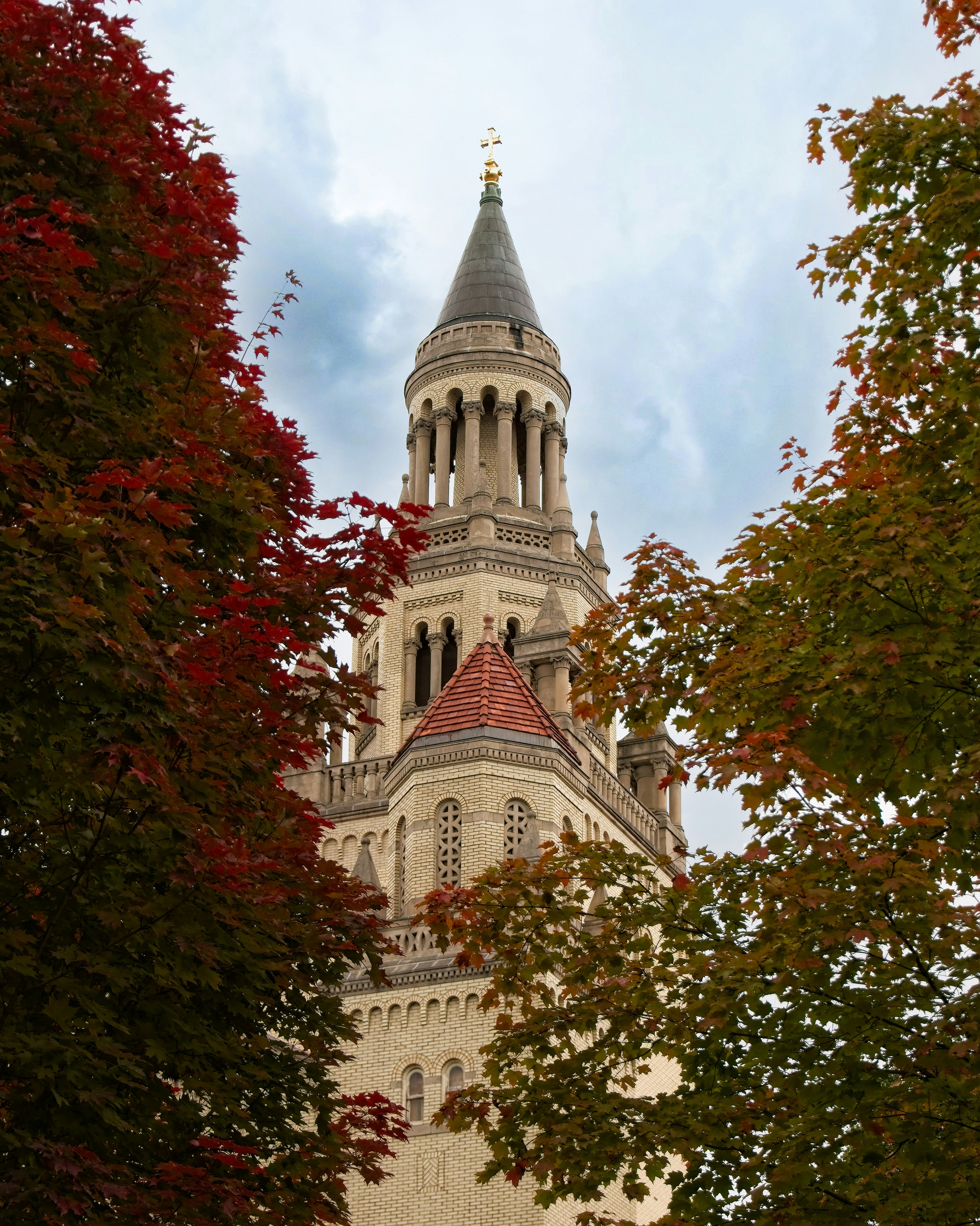 Autumn Spire: Cathedral Tower Cutting Through Crimson and Gold Foliage