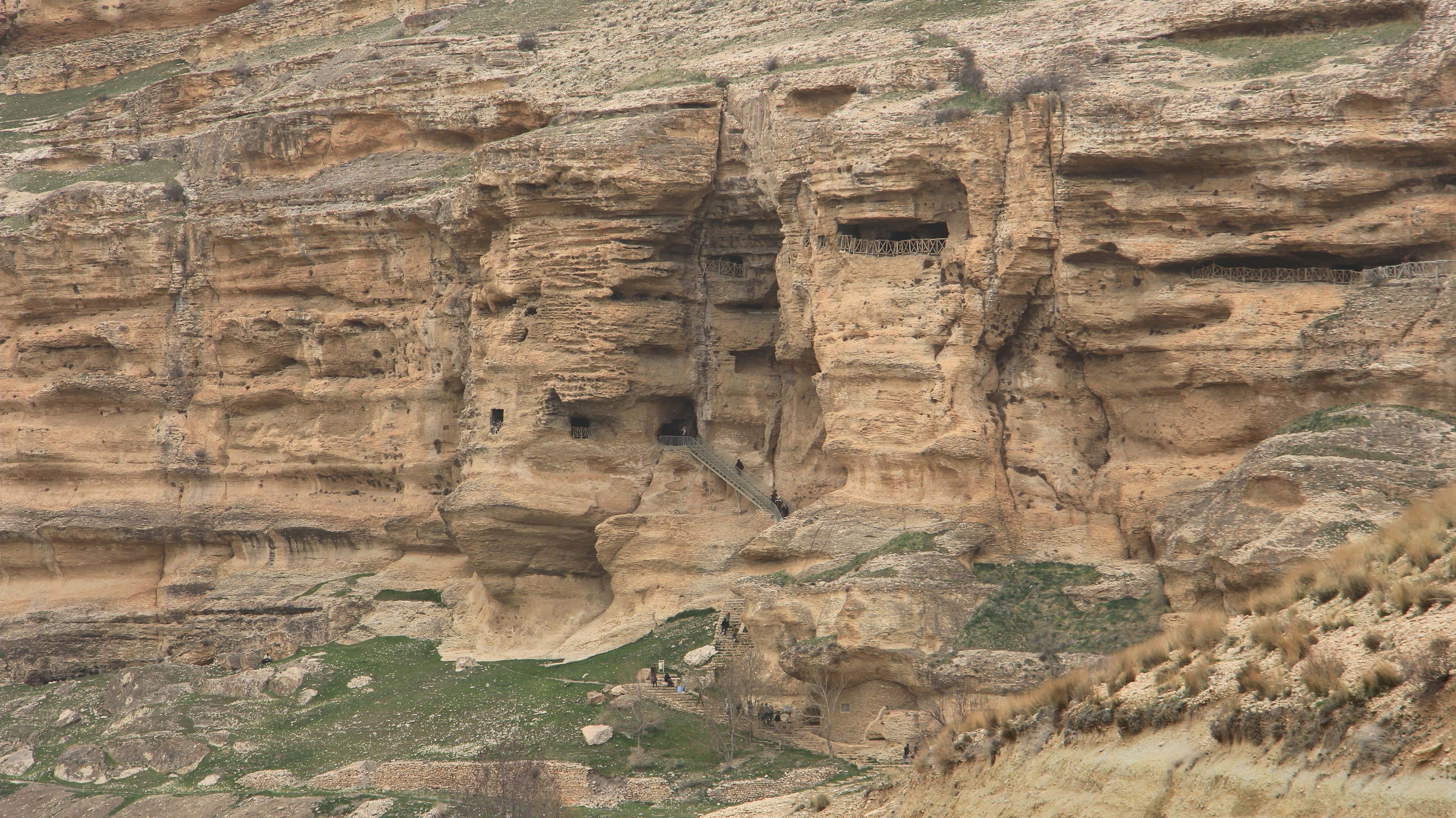 A rocky cliff with a small cave in the middle of it photo – Free Cliff ...