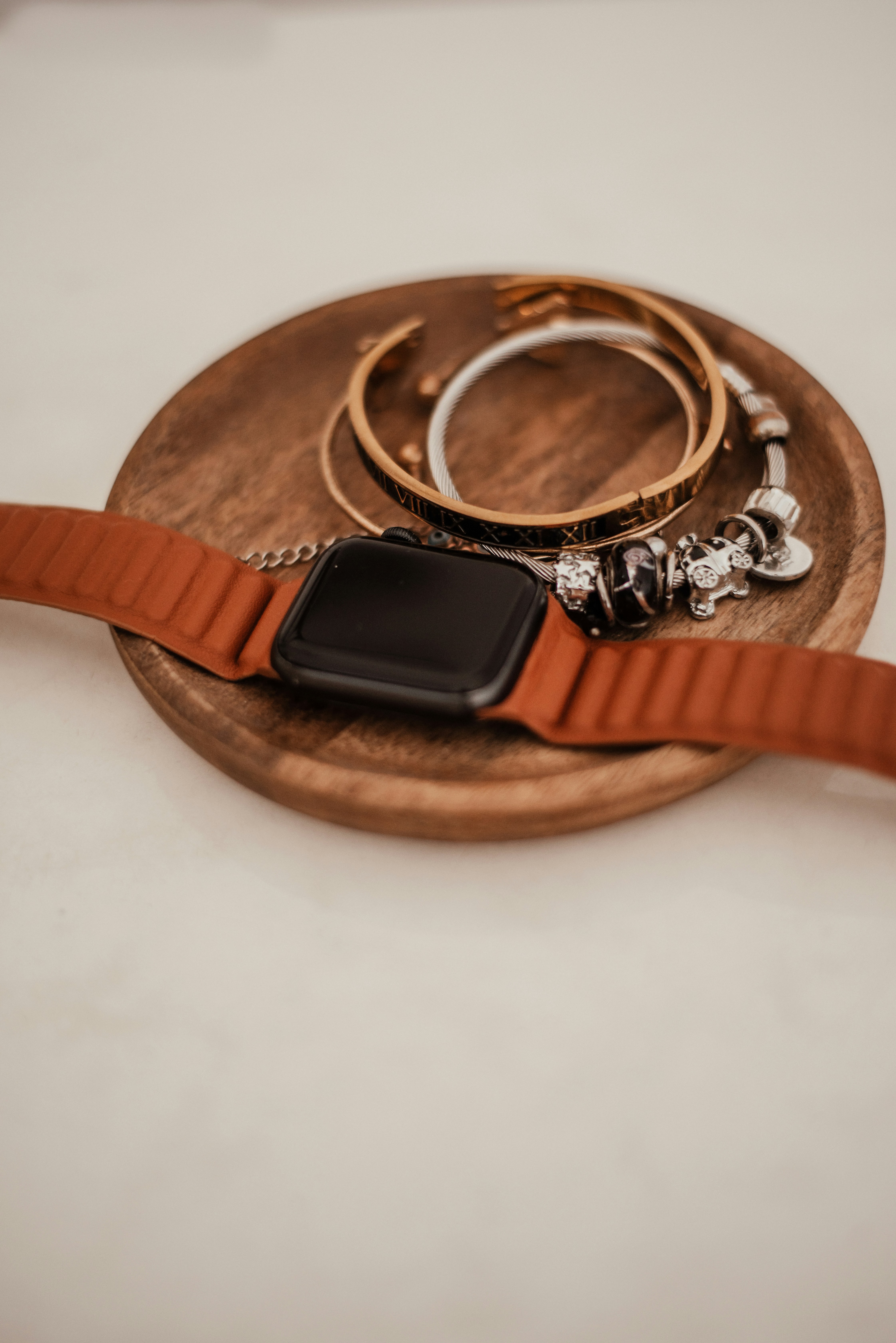 Orange-Wrapped Time: A Quiet Still-Life of Jewelry and a Smartwatch on Wood