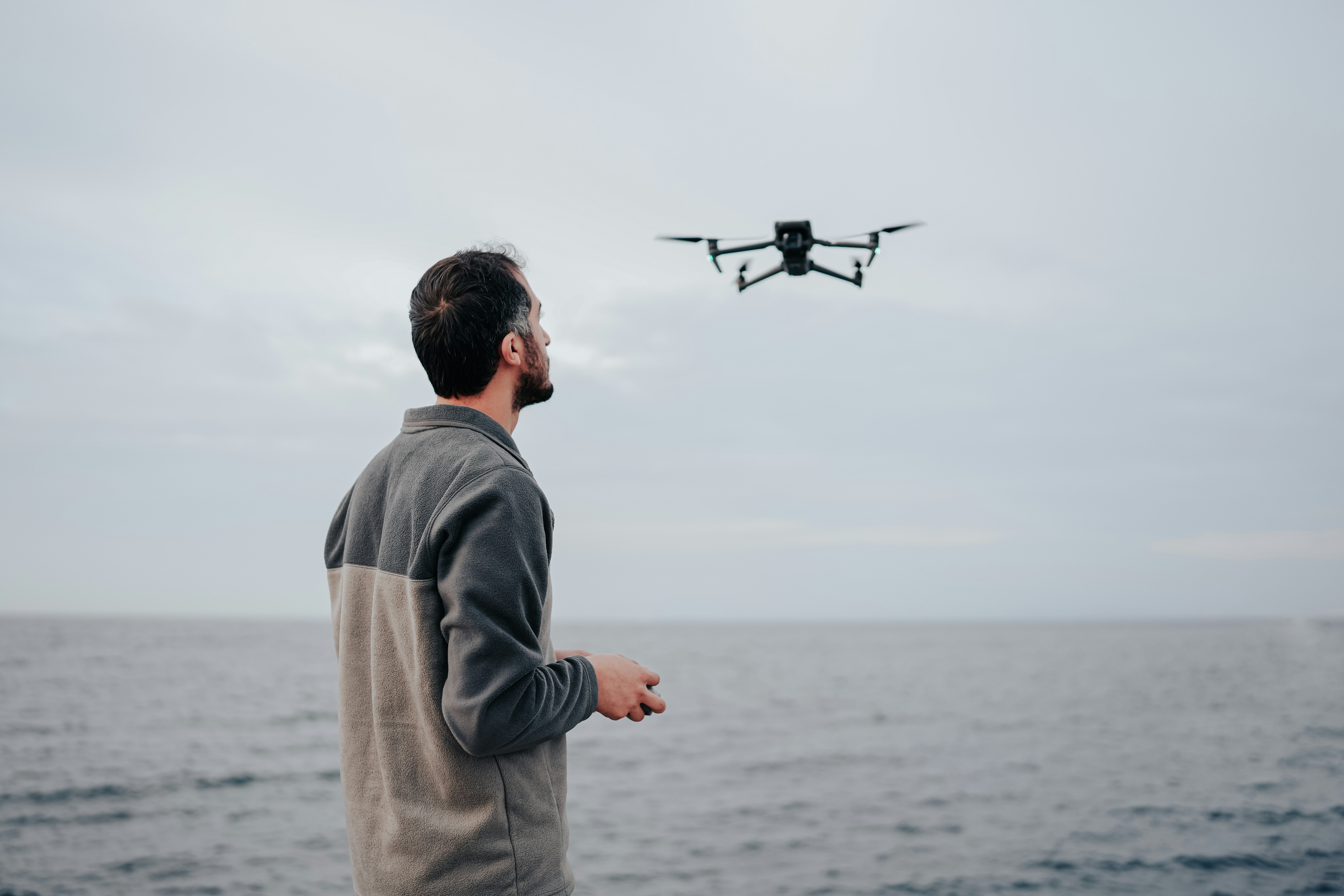 A man looking at a flying object over the ocean photo – Free Man Image on Unsplash