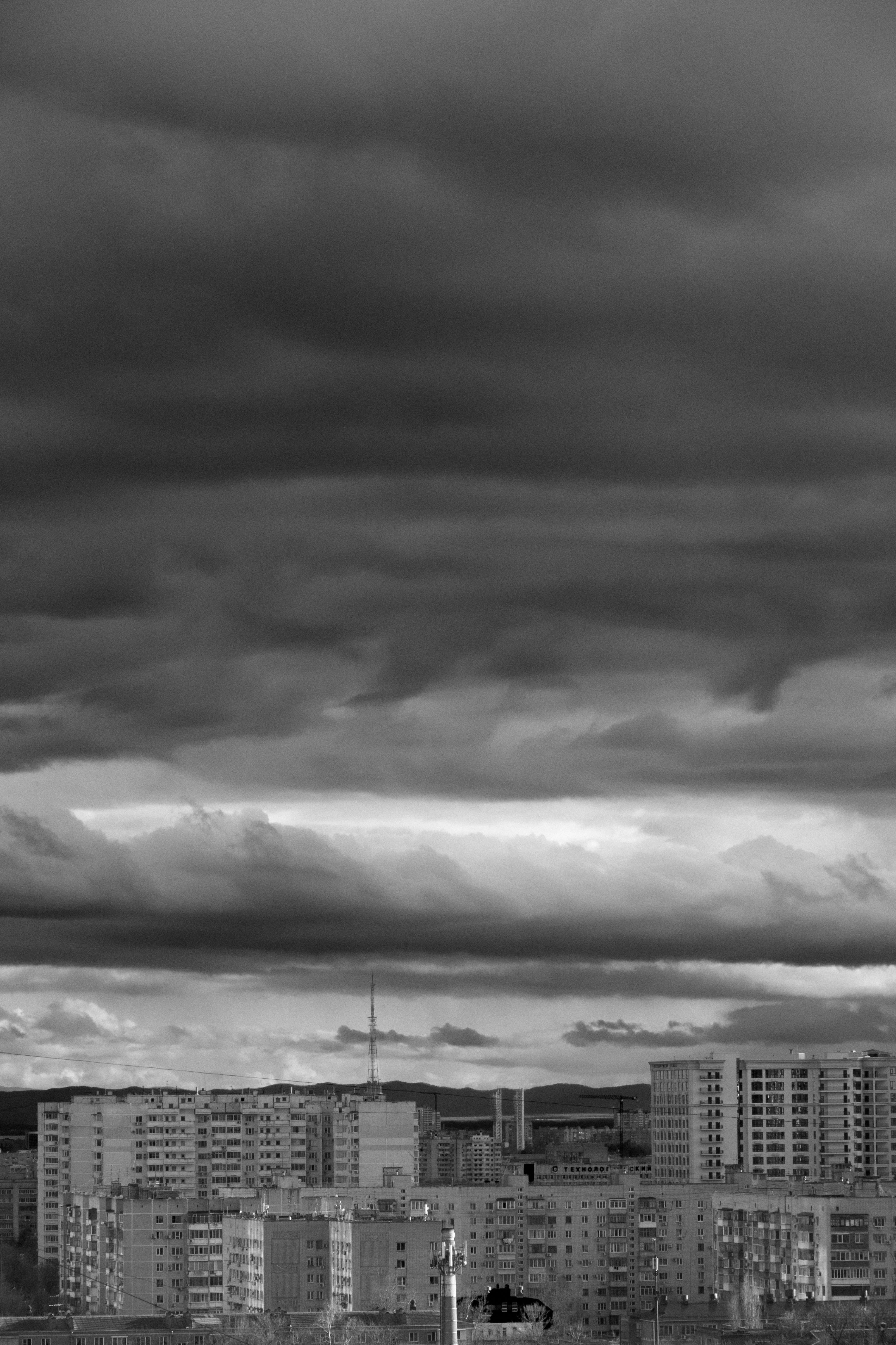 a black and white photo of a city under a cloudy sky
