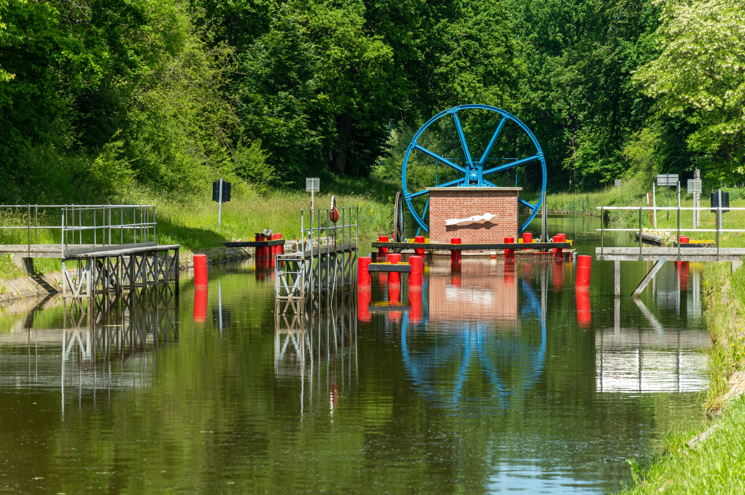 Azure Wheel at a Quiet Canal Lock, Framed by Greenery