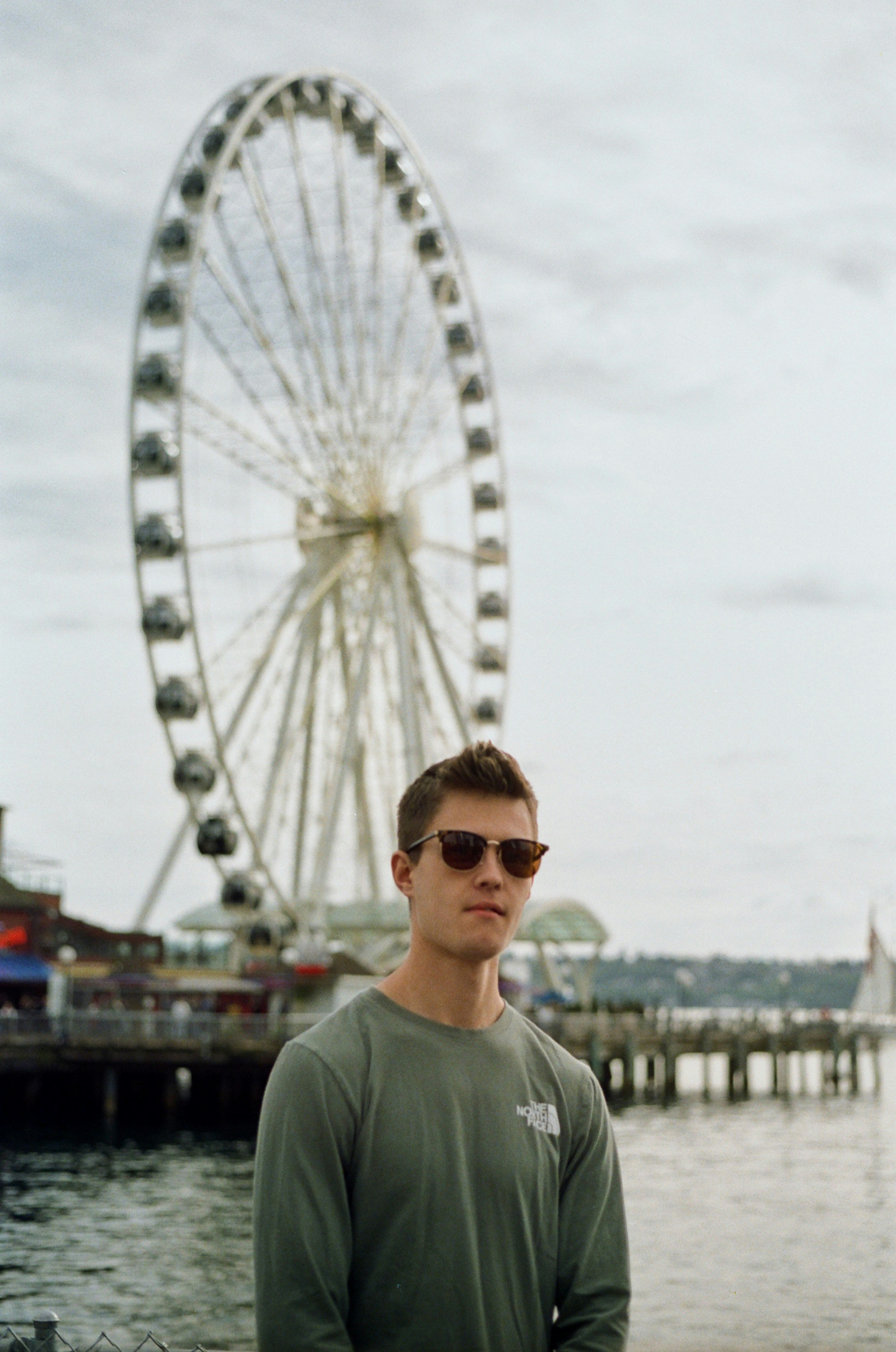 A man standing in front of a large ferris wheel photo – Free Portrait ...