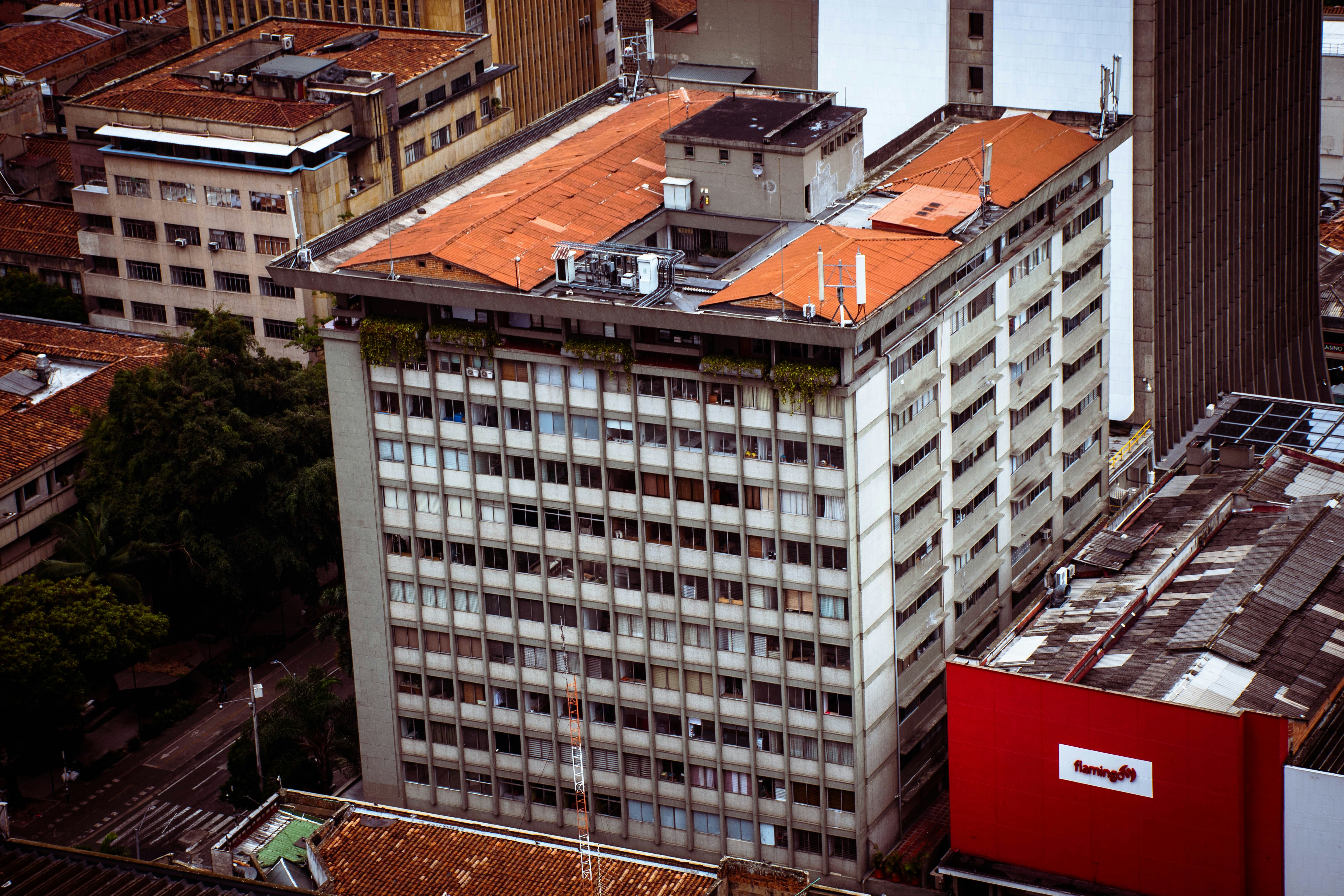 High-rise building with a grid of windows and terracotta roof amid urban landscape.
