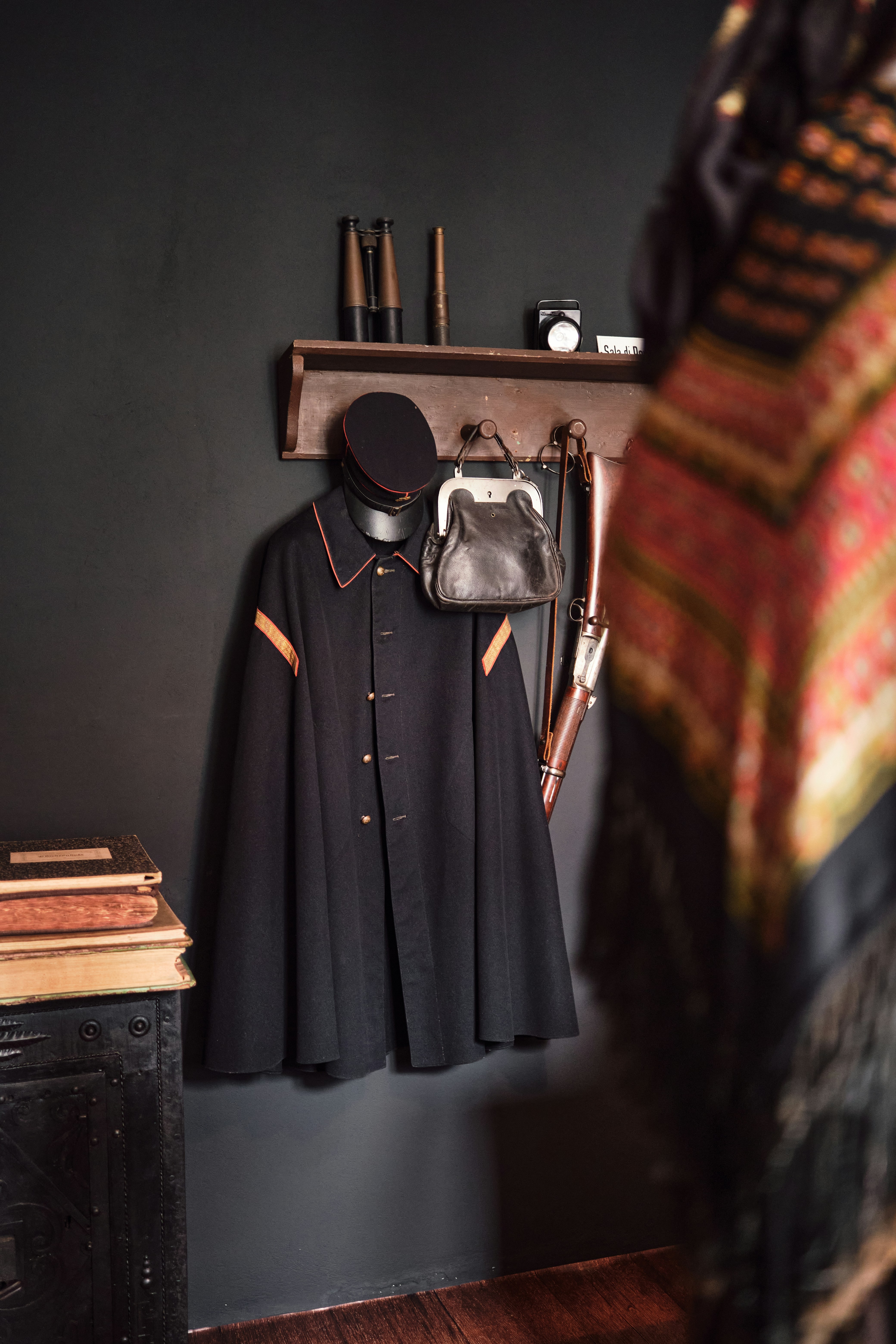 Midnight Wardrobe: A Vintage Coat with Orange Trim in a Shadowed Studio