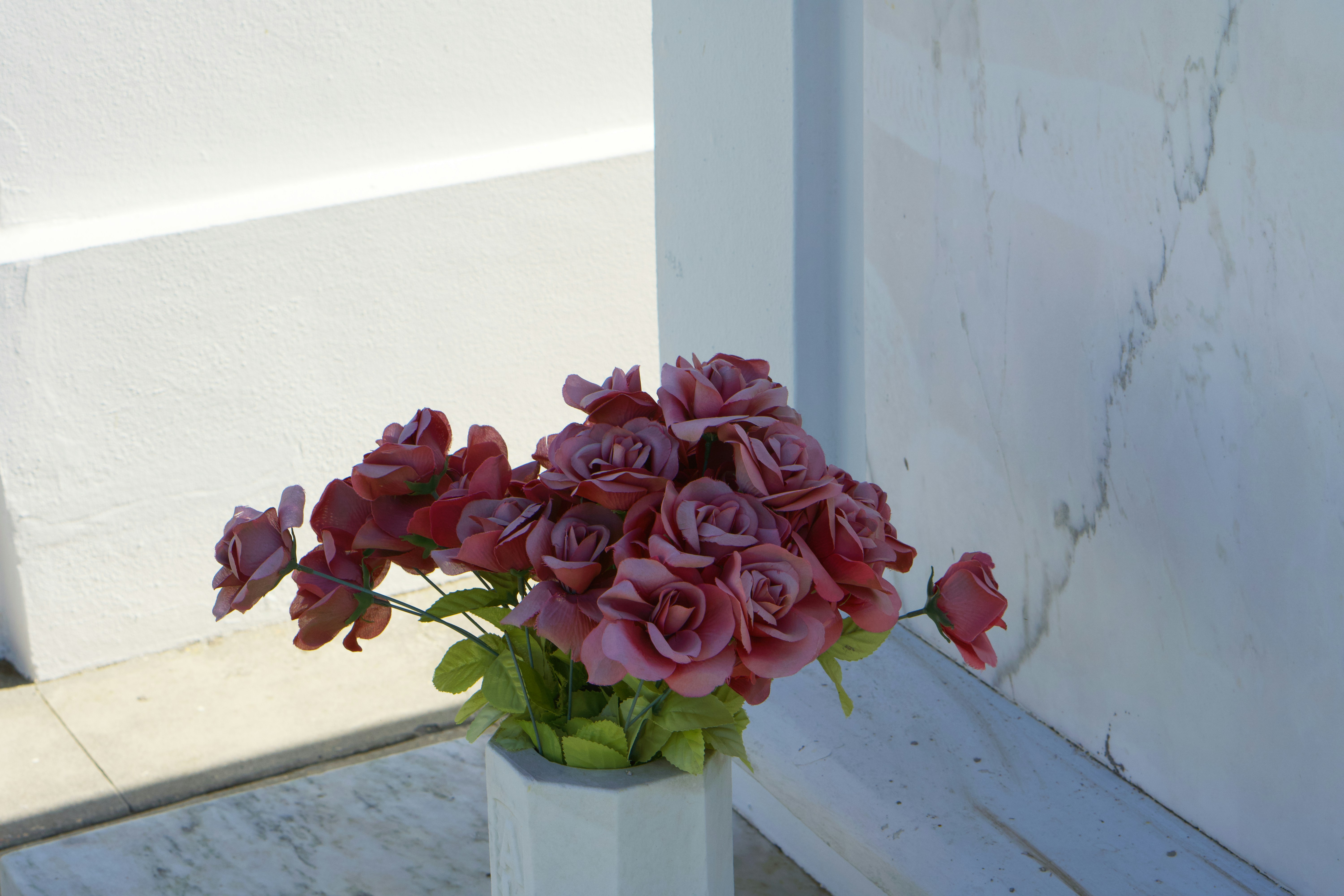 a white vase filled with pink flowers sitting on a window sill