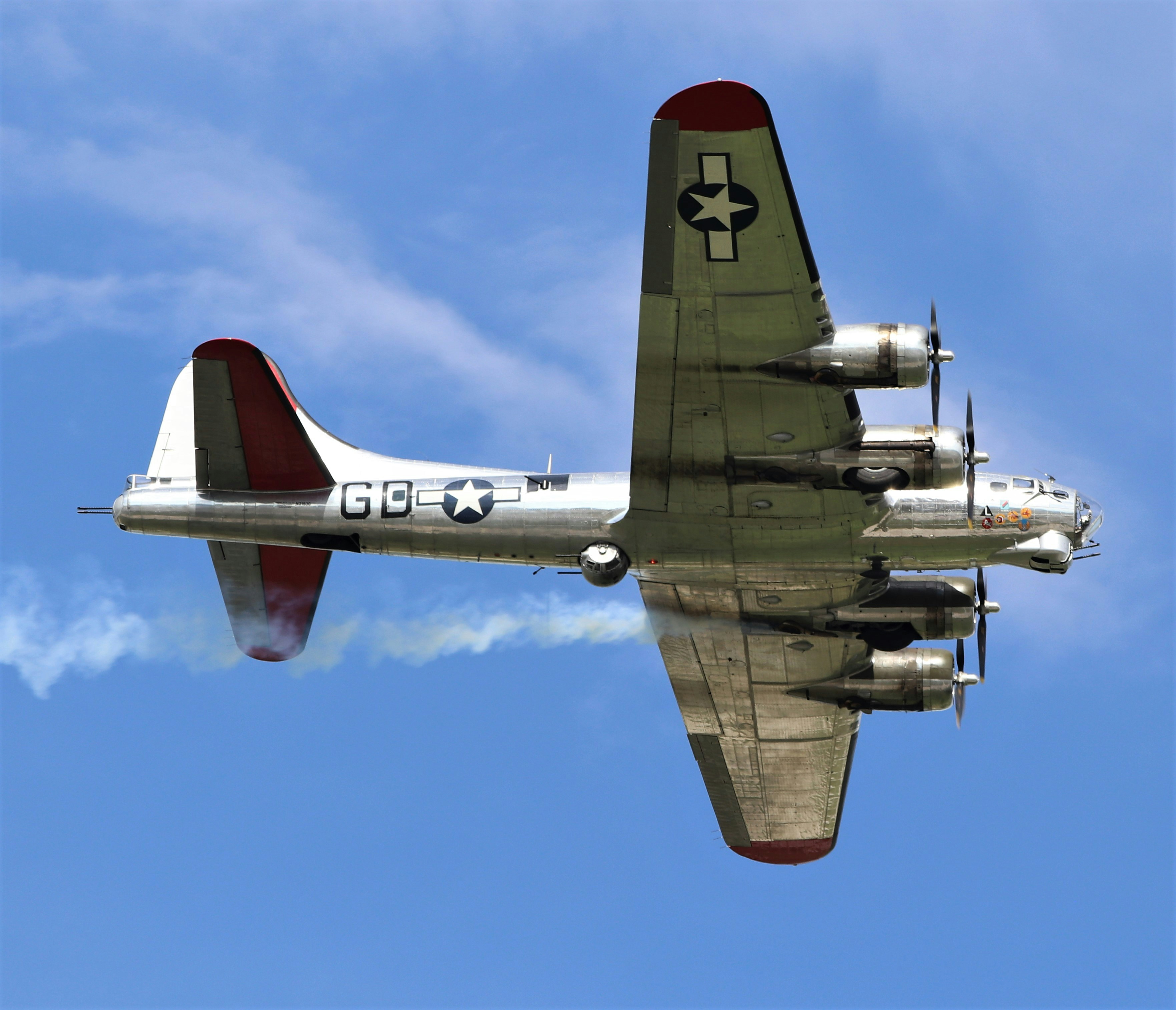 Plane at London AIrshow | a silver and red airplane flying through a blue sky