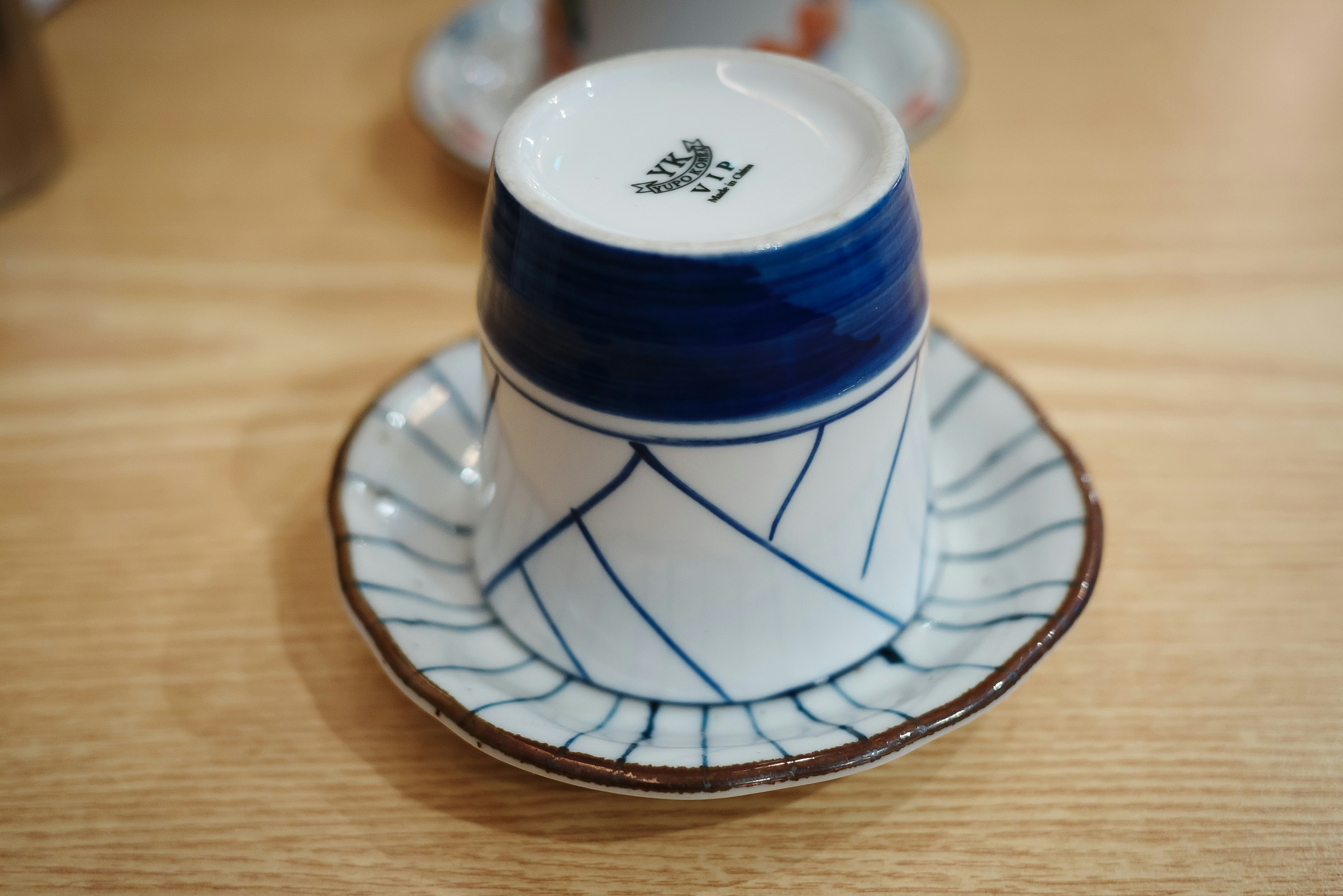Blue-Geometric Porcelain Cup Resting on a Pale Wooden Table