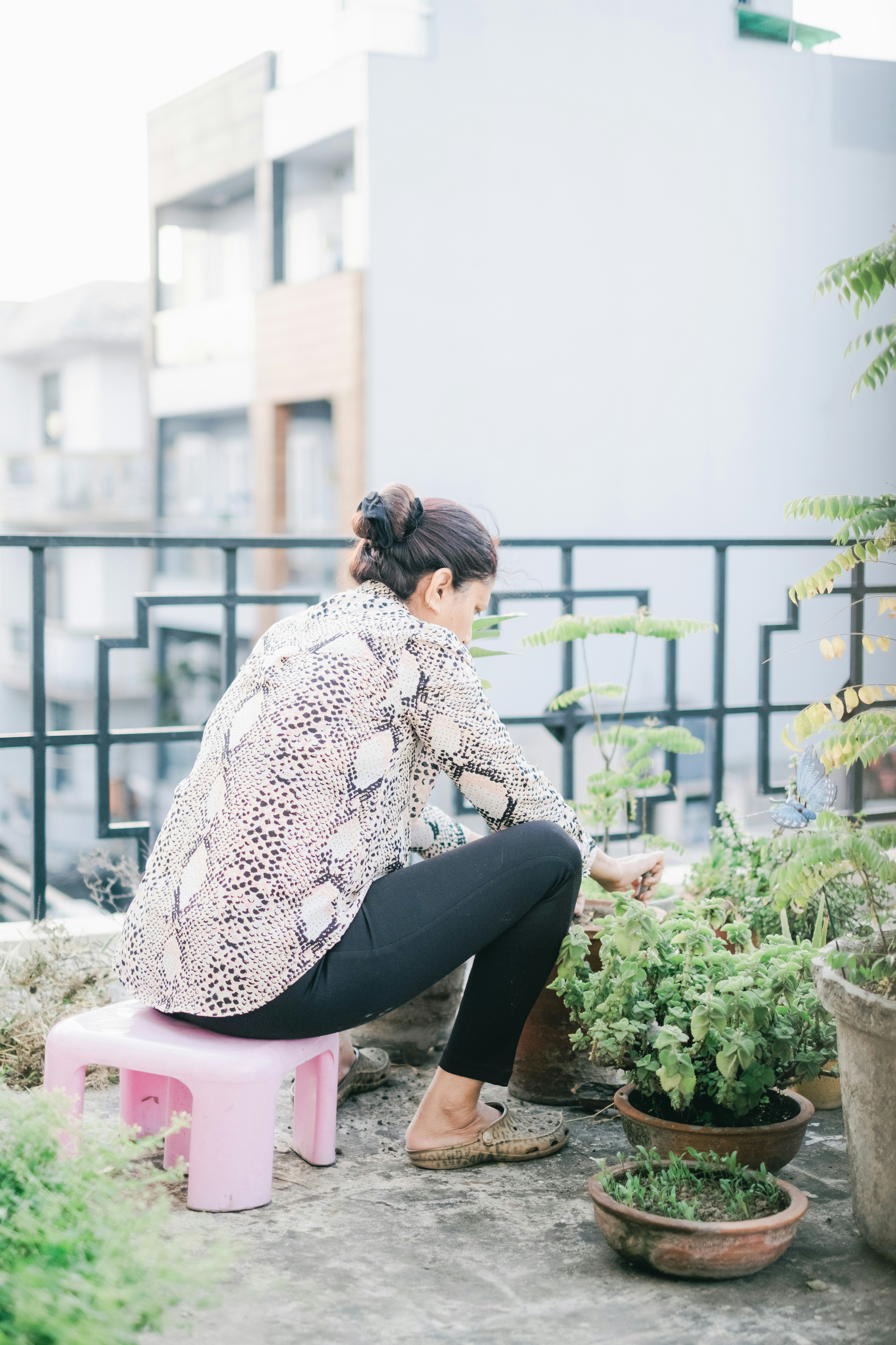 a woman sitting on a bench in front of potted plants