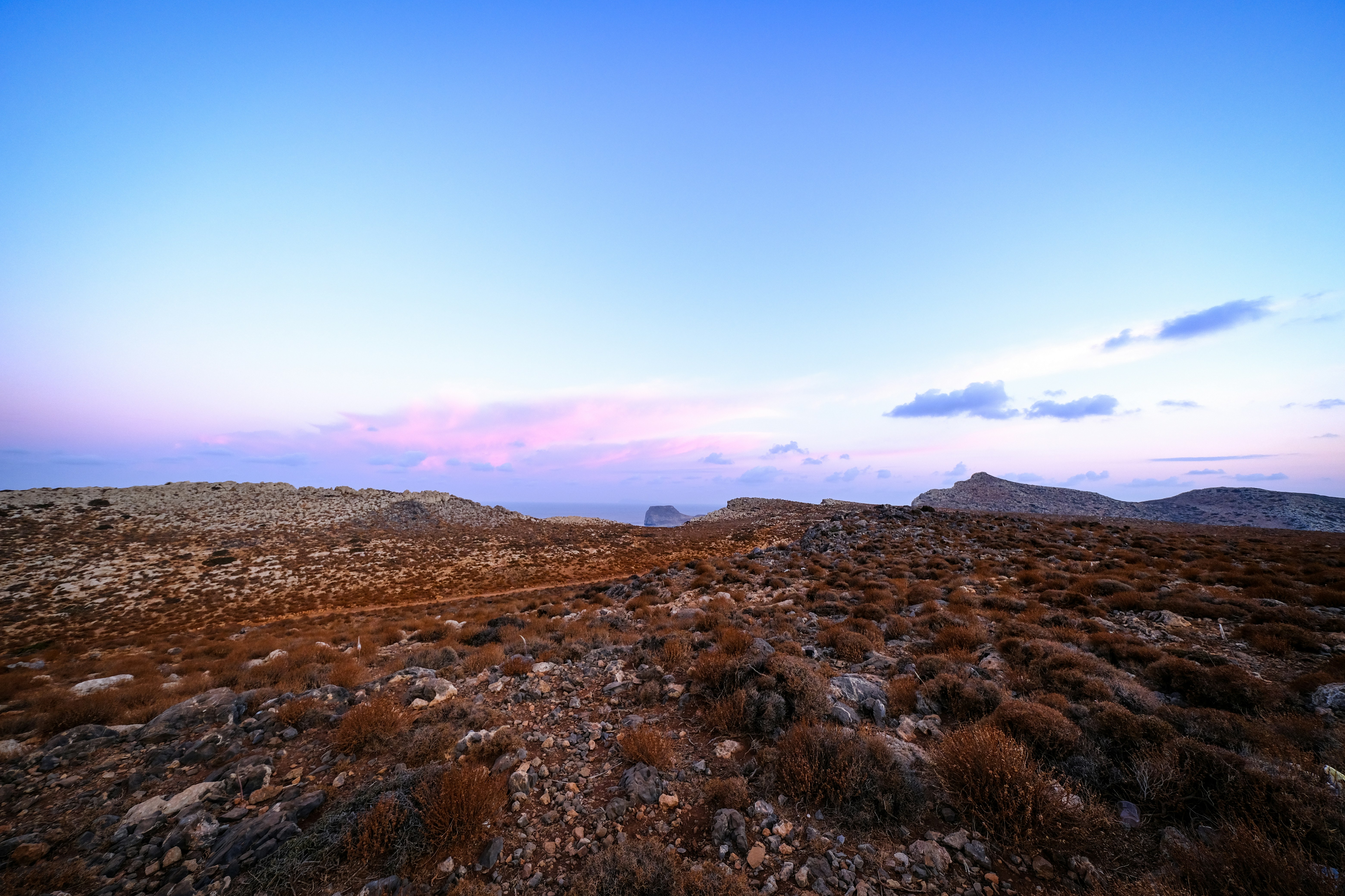 A rocky field with grass and rocks under a blue sky photo – Free Ground ...