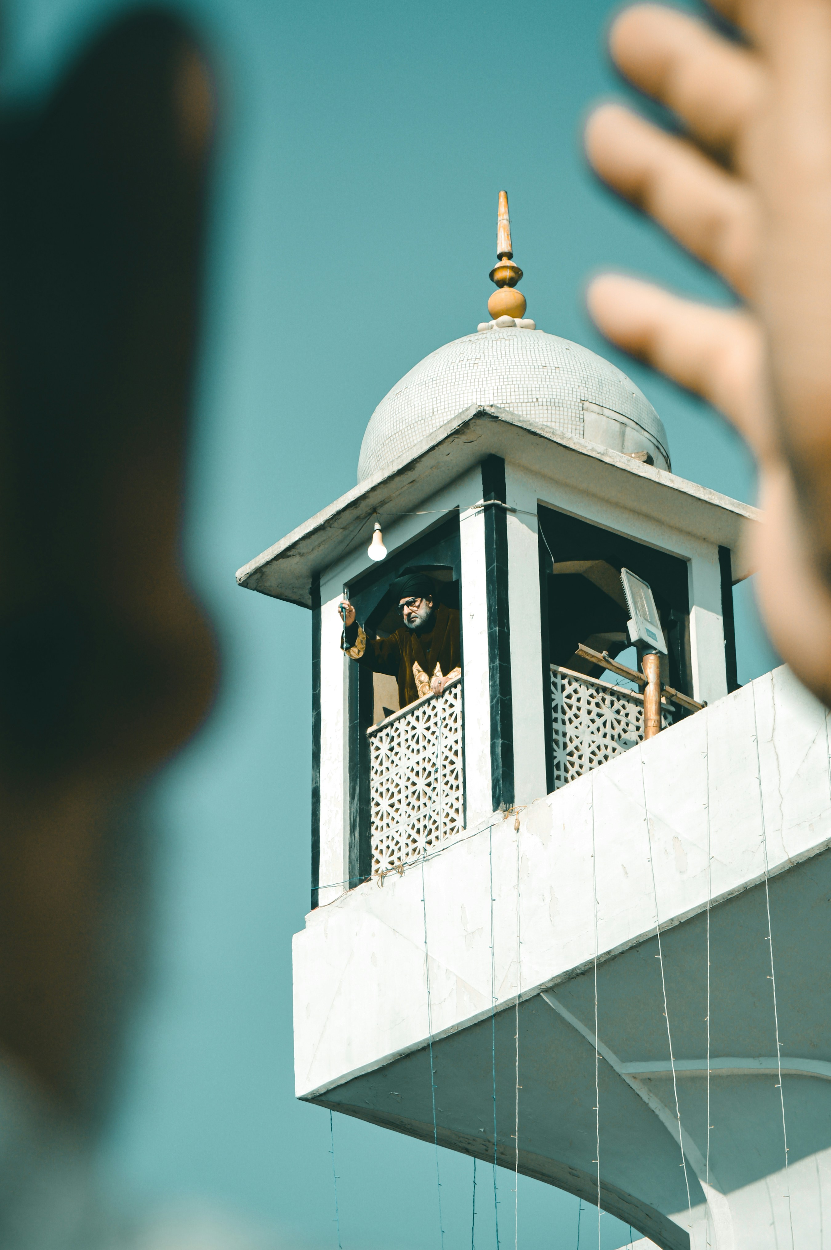 a man praying to god while a person show holy relic of Prophet muhammad عَلَيْهِ ٱلسَّلَامُ to a crowd of people from the corner place of Dargah Hazratbal Kashmir (This image can be used commercially and personally)