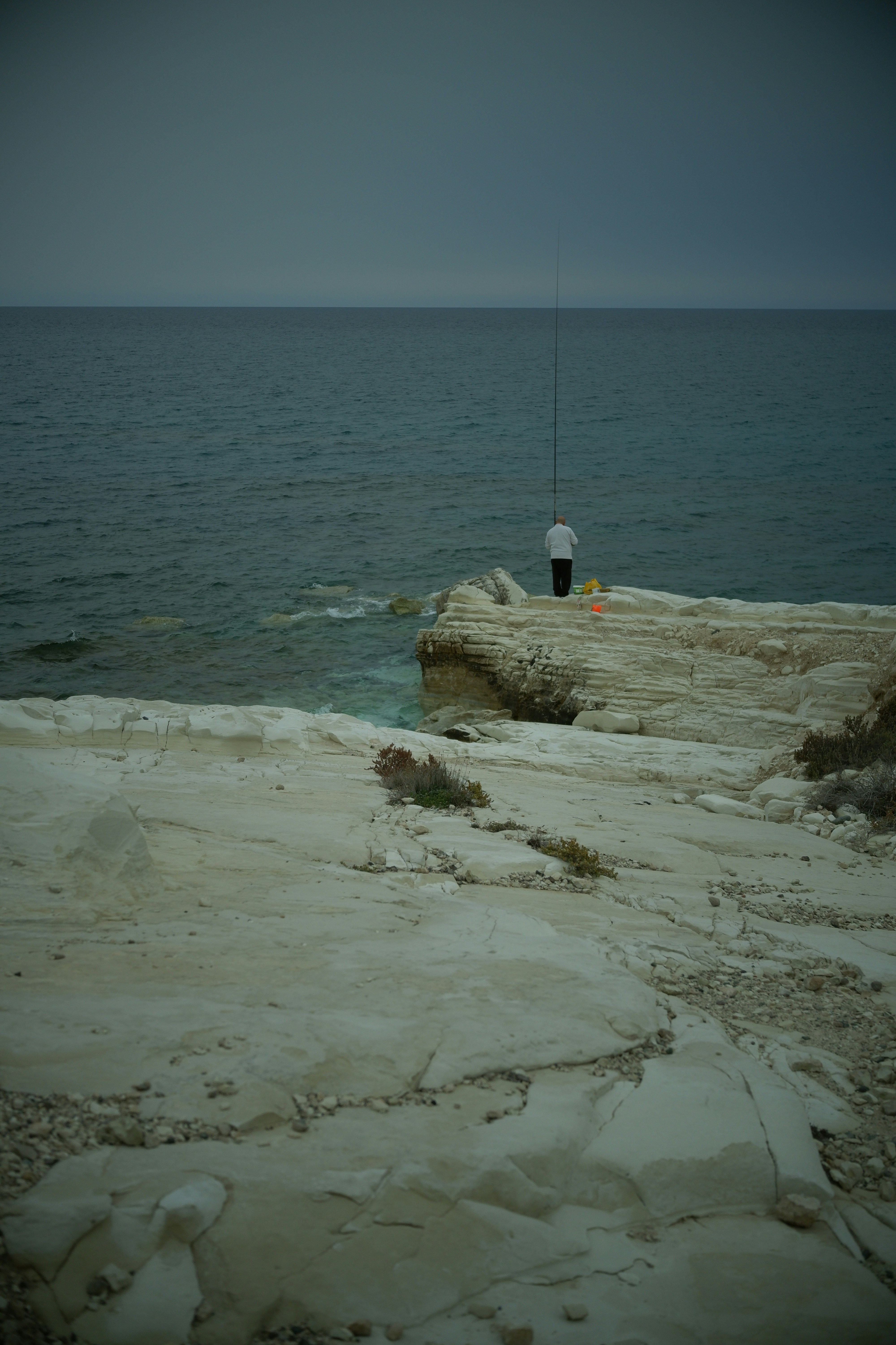 a person sitting on a rock with a fishing pole