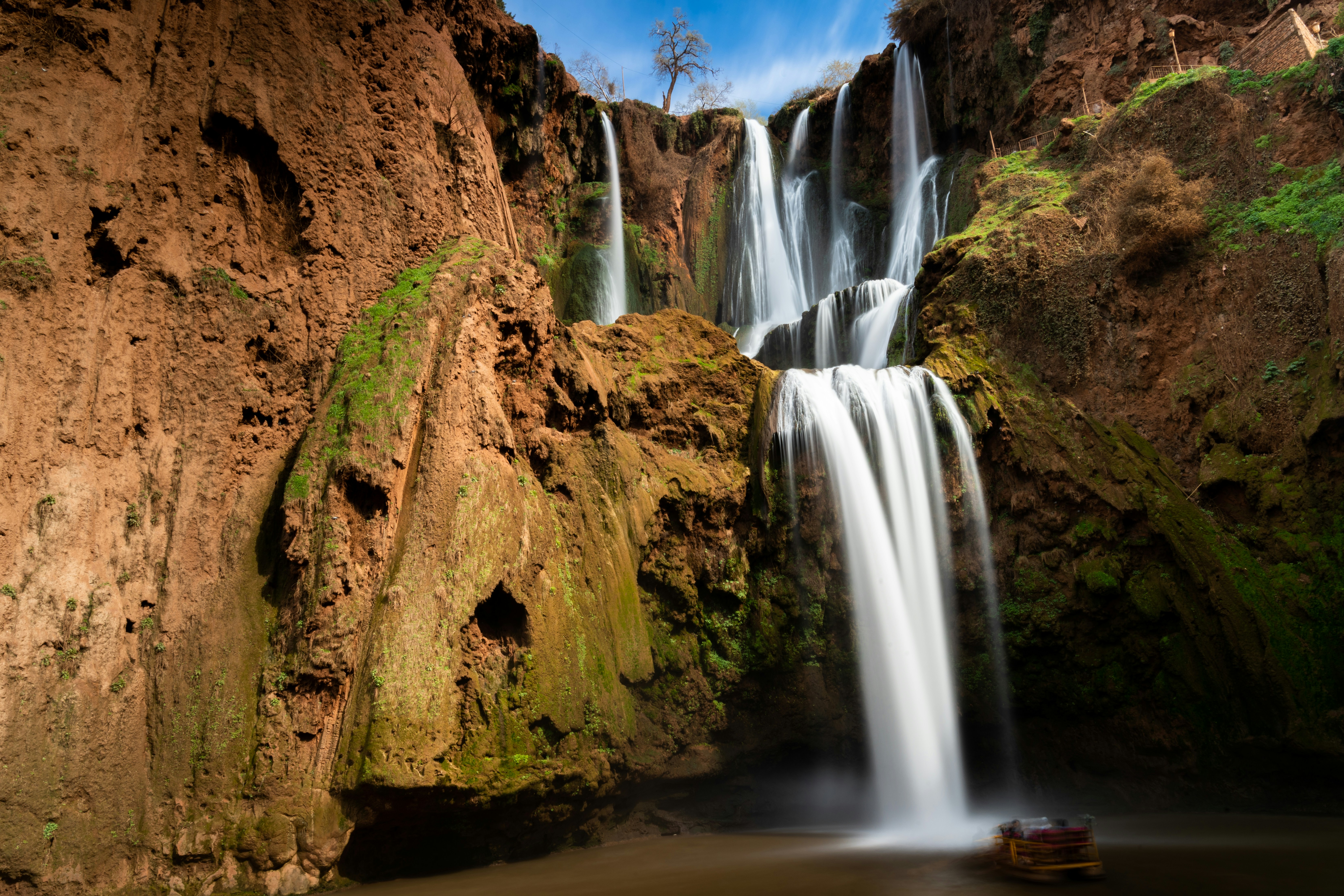 waterfall on the way | a boat is in the water near a waterfall