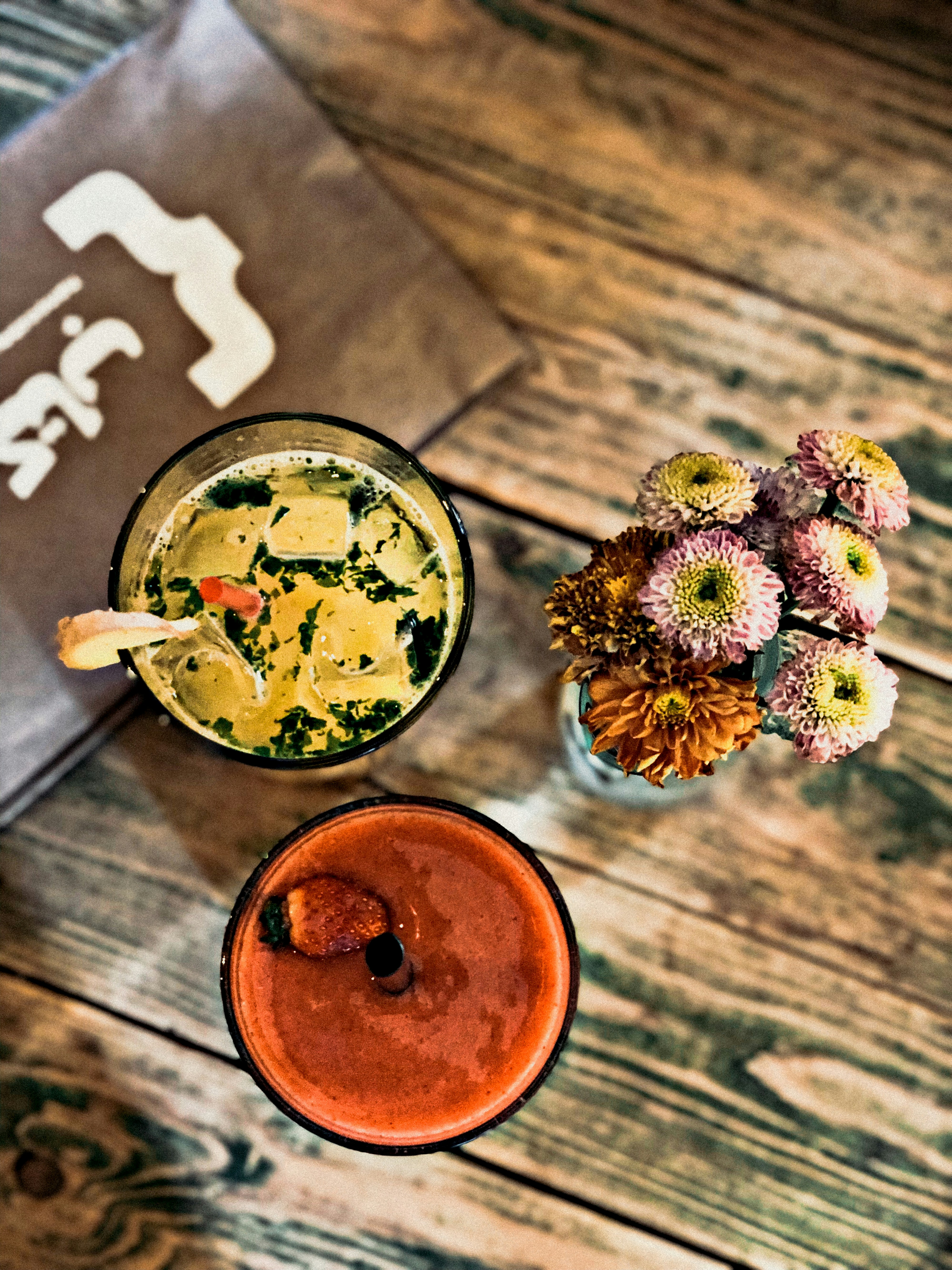 Overhead Sip Scene: Two Cocktails, One Rustic Table, One Blooming Accent