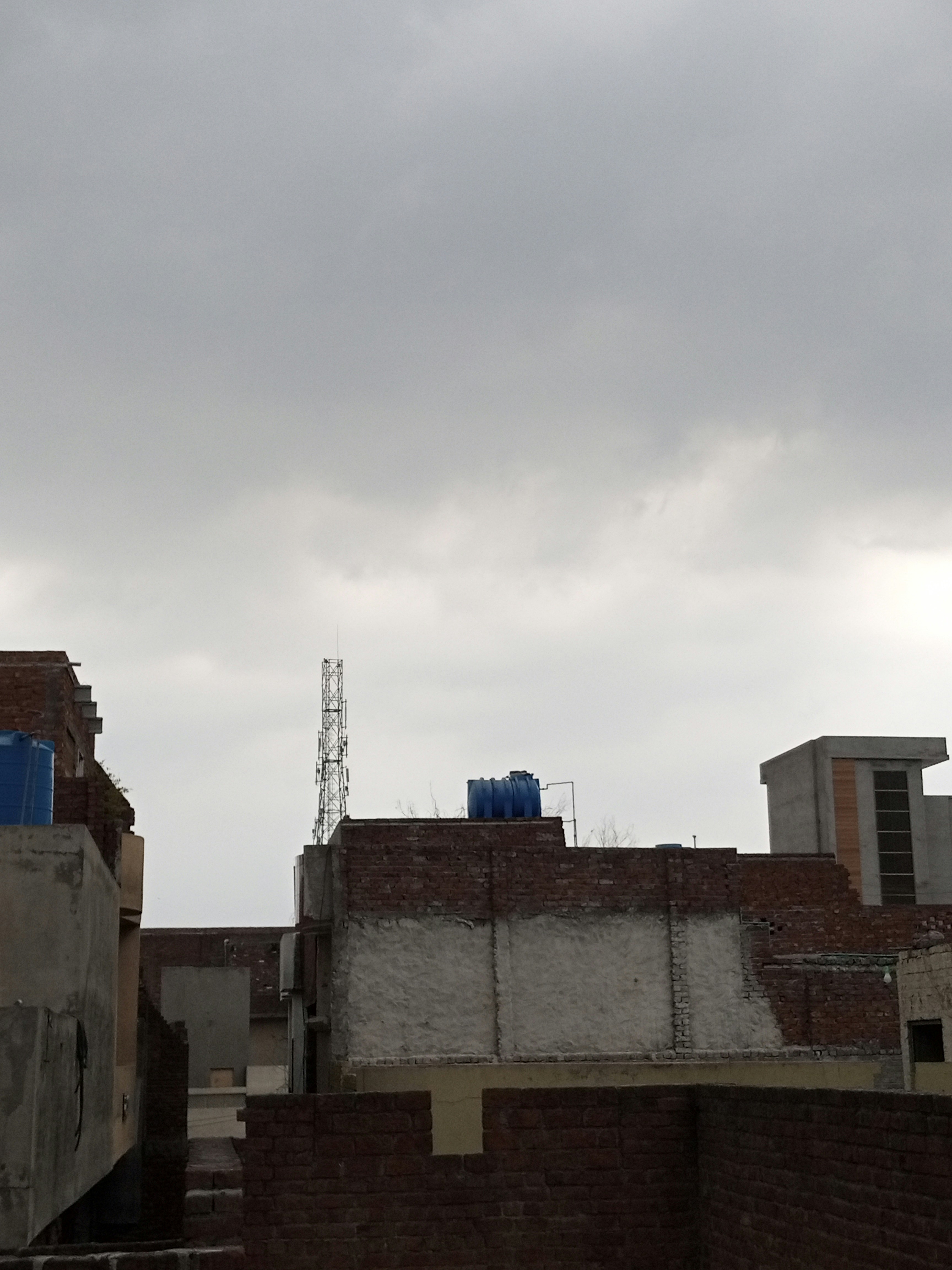 Urban rooftops form a jagged horizon beneath a heavy overcast sky.