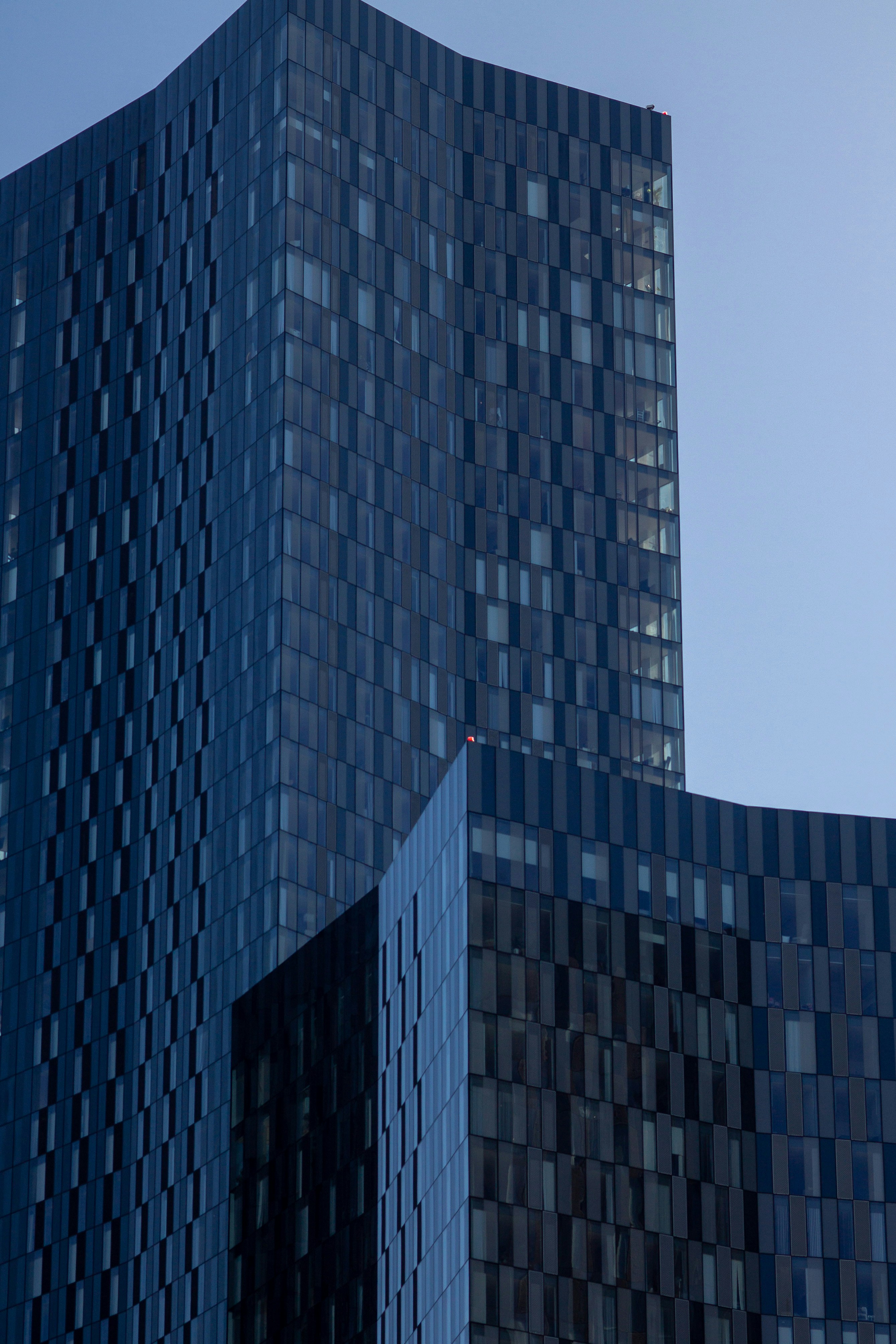 A very tall building with a plane flying in front of it photo – Free ...