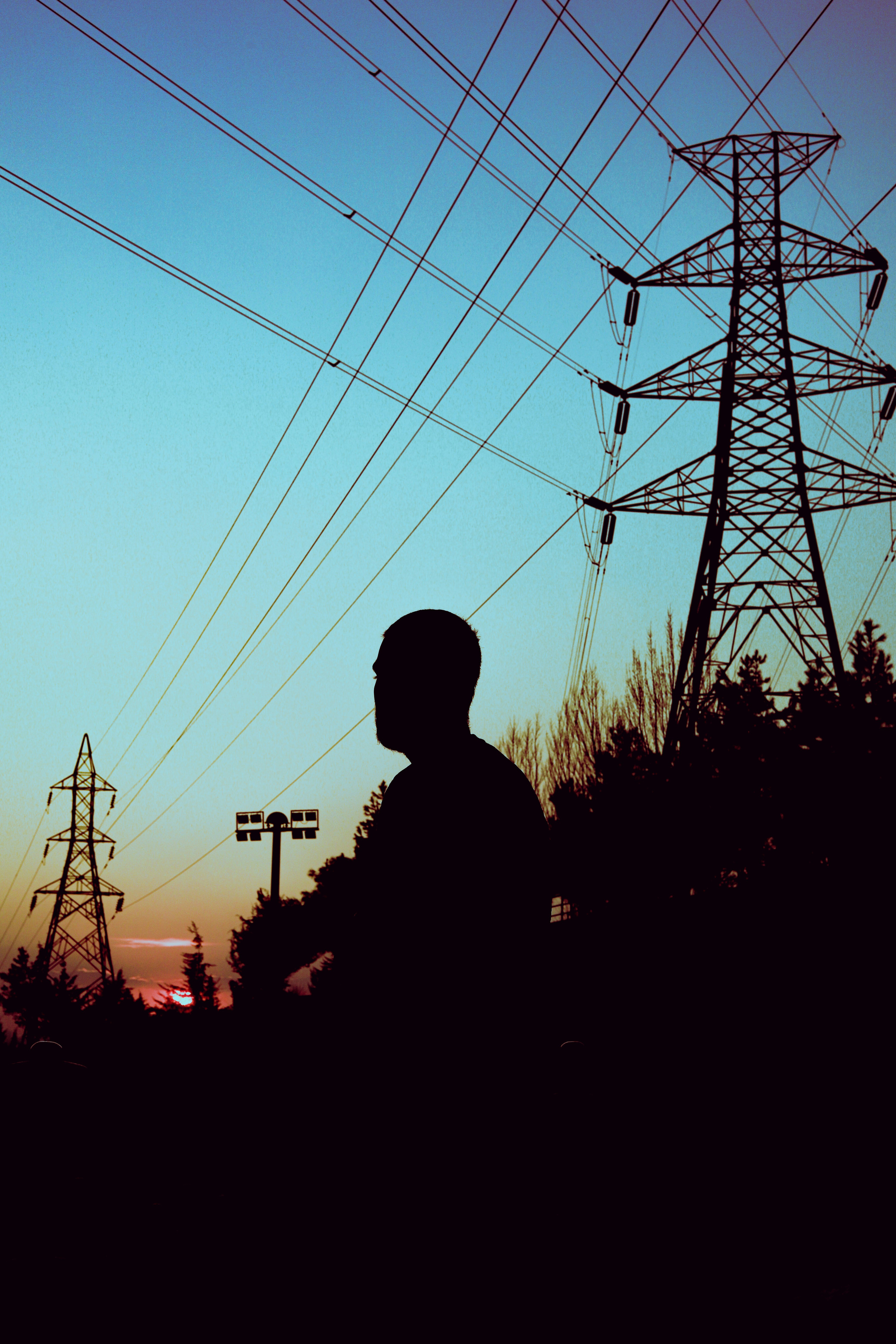 Silhouette Beneath a Web of Transmission Lines at Dusk