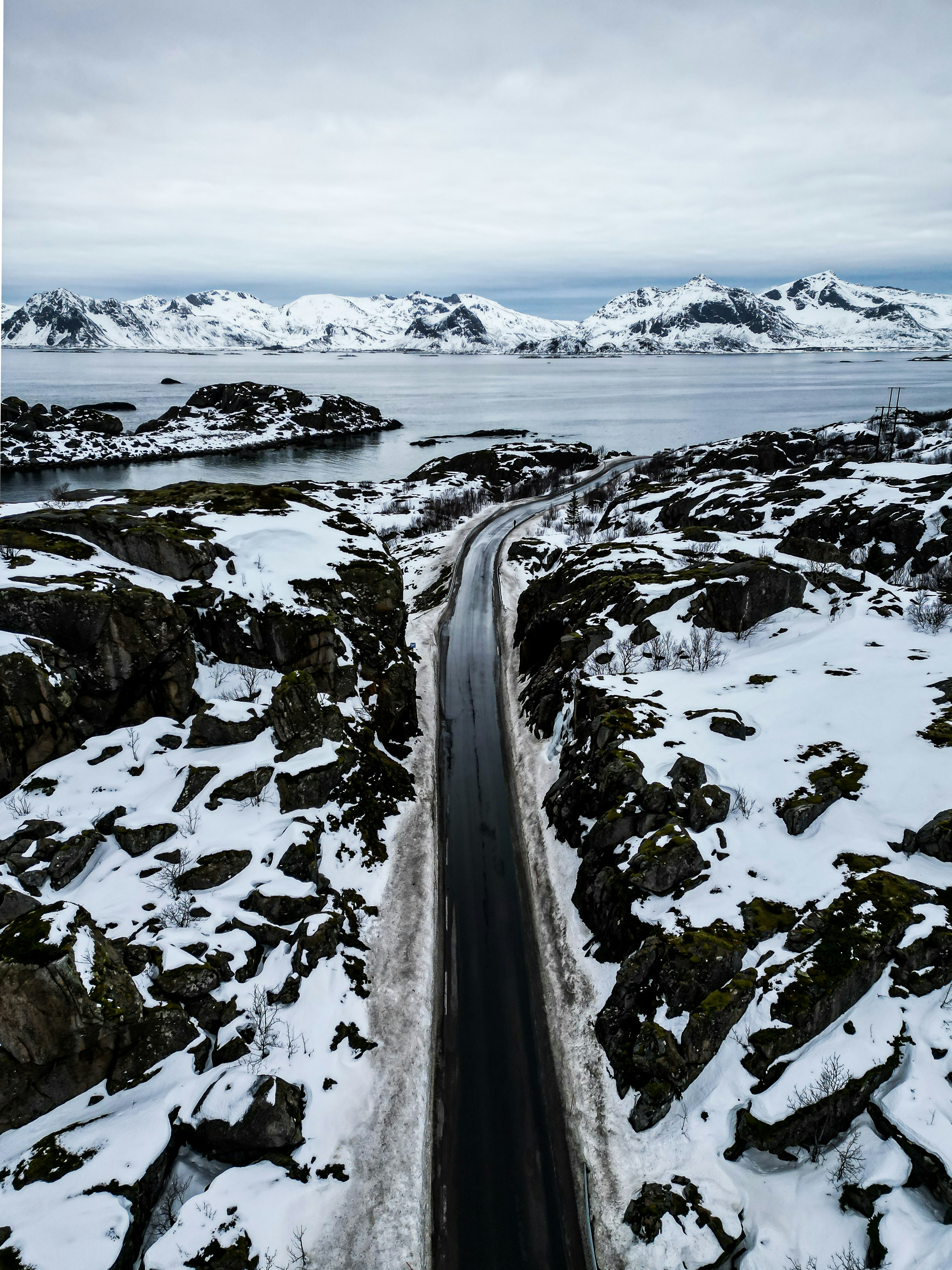 Snowbound Fjord: A Winding Road Carves Through Rugged Coast Toward Distant Peaks