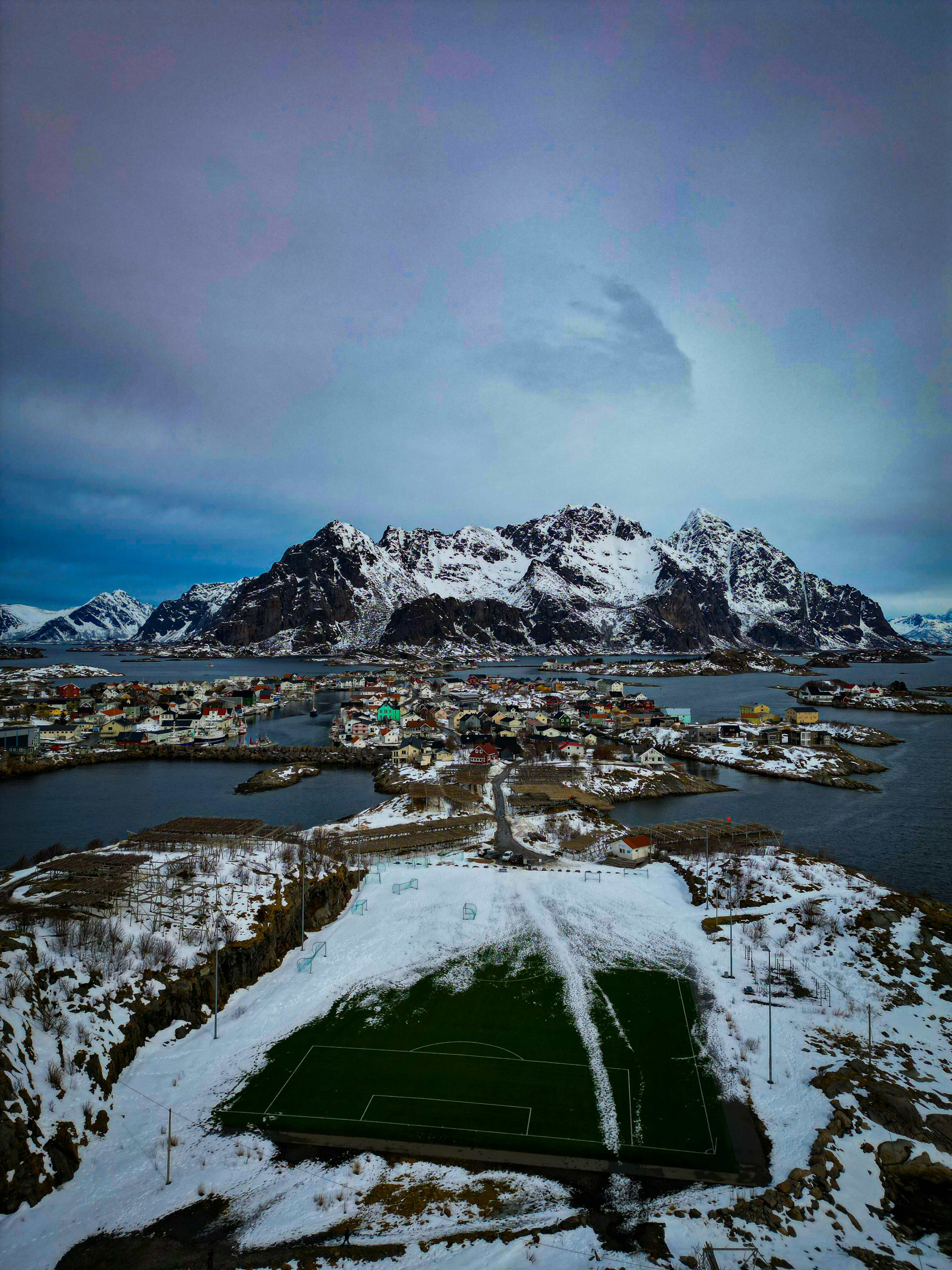 The beautiful and popular football field on a little island in Henningsvær Henningsvaer, Lofoten, Norway. Snowcovered mountains in the background. Taken with a drone.