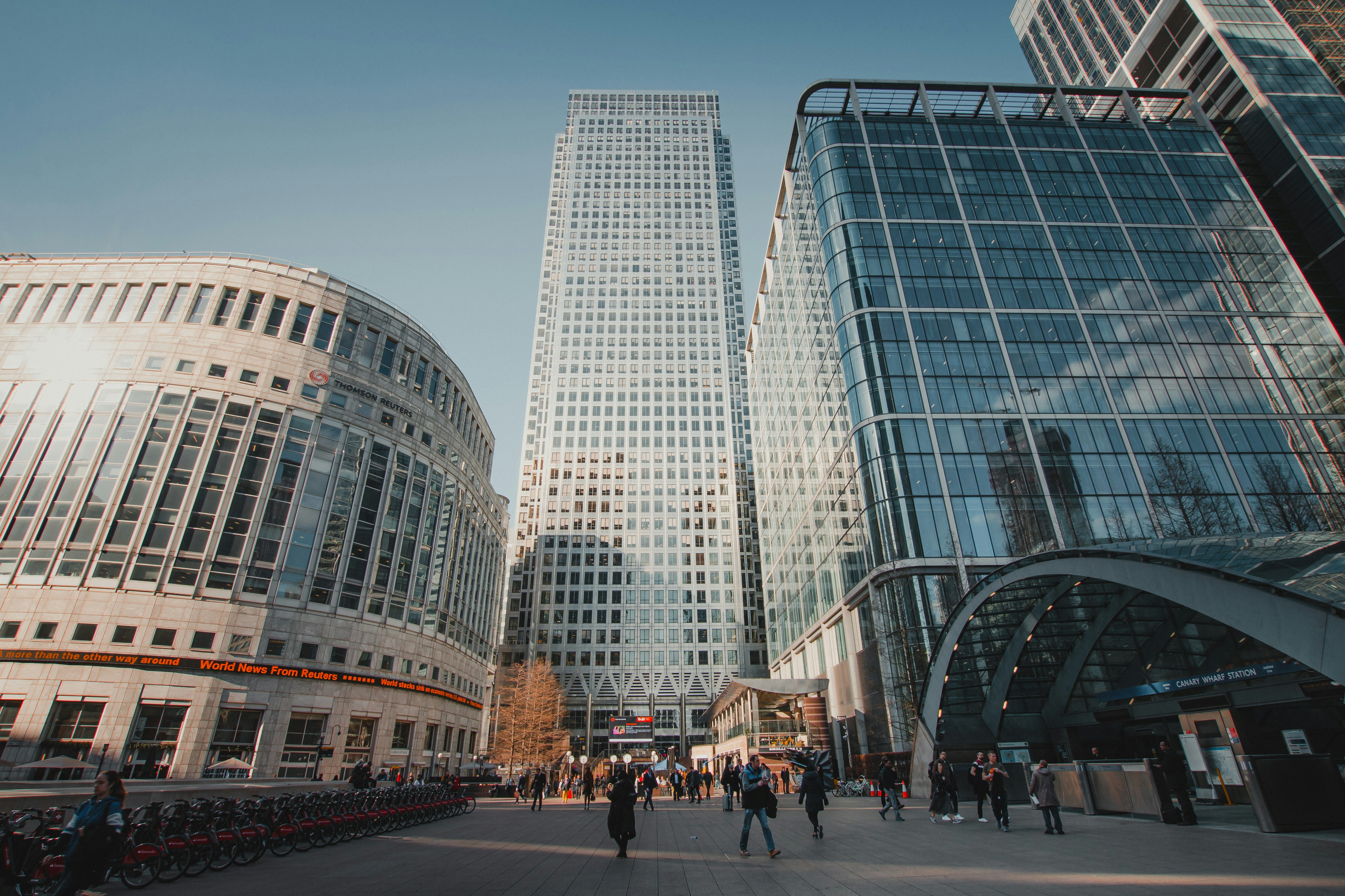 A group of people walking down a street next to tall buildings photo ...
