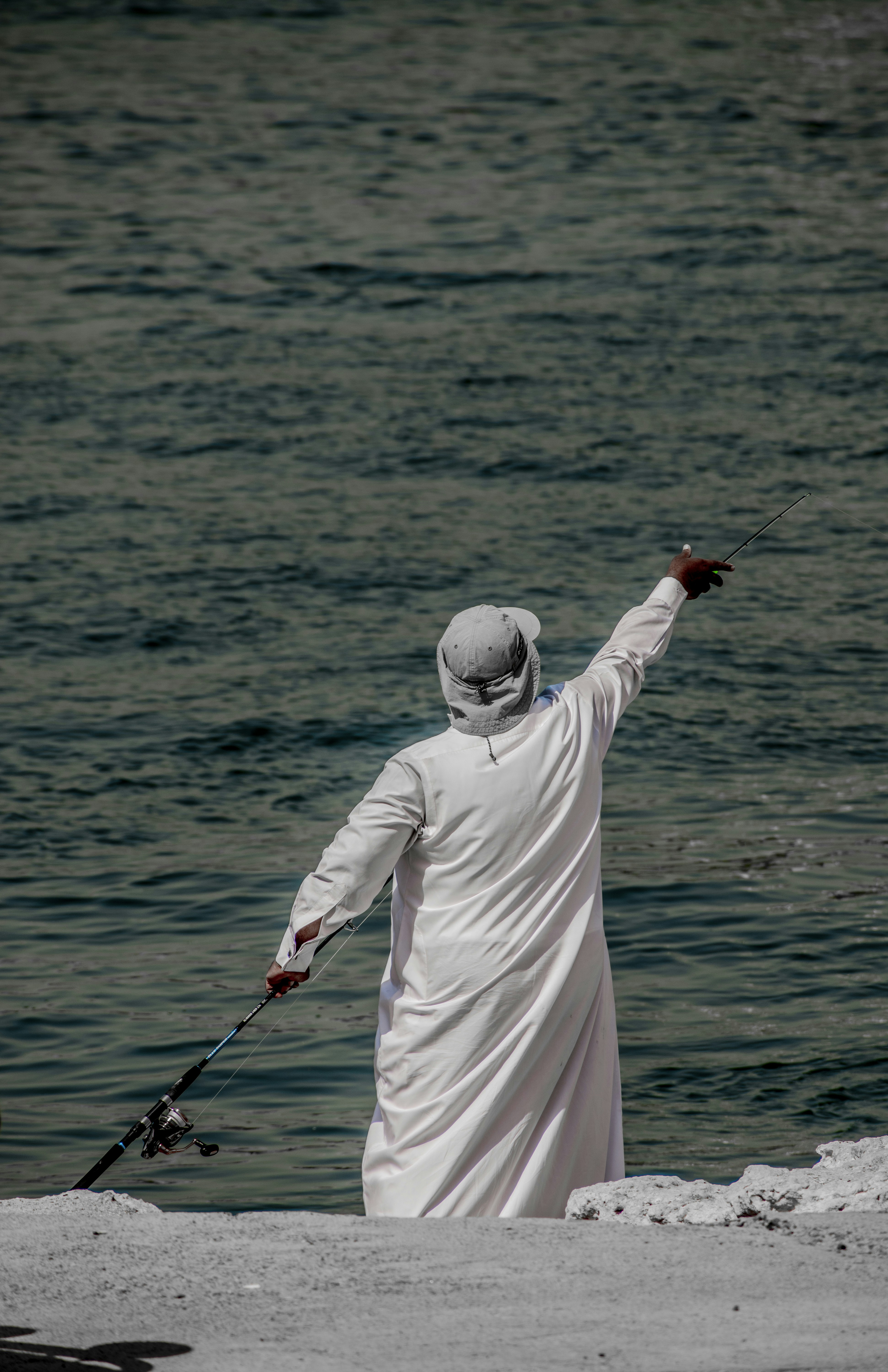 A man in a white robe holding a fishing rod photo – Free Dubai - united ...