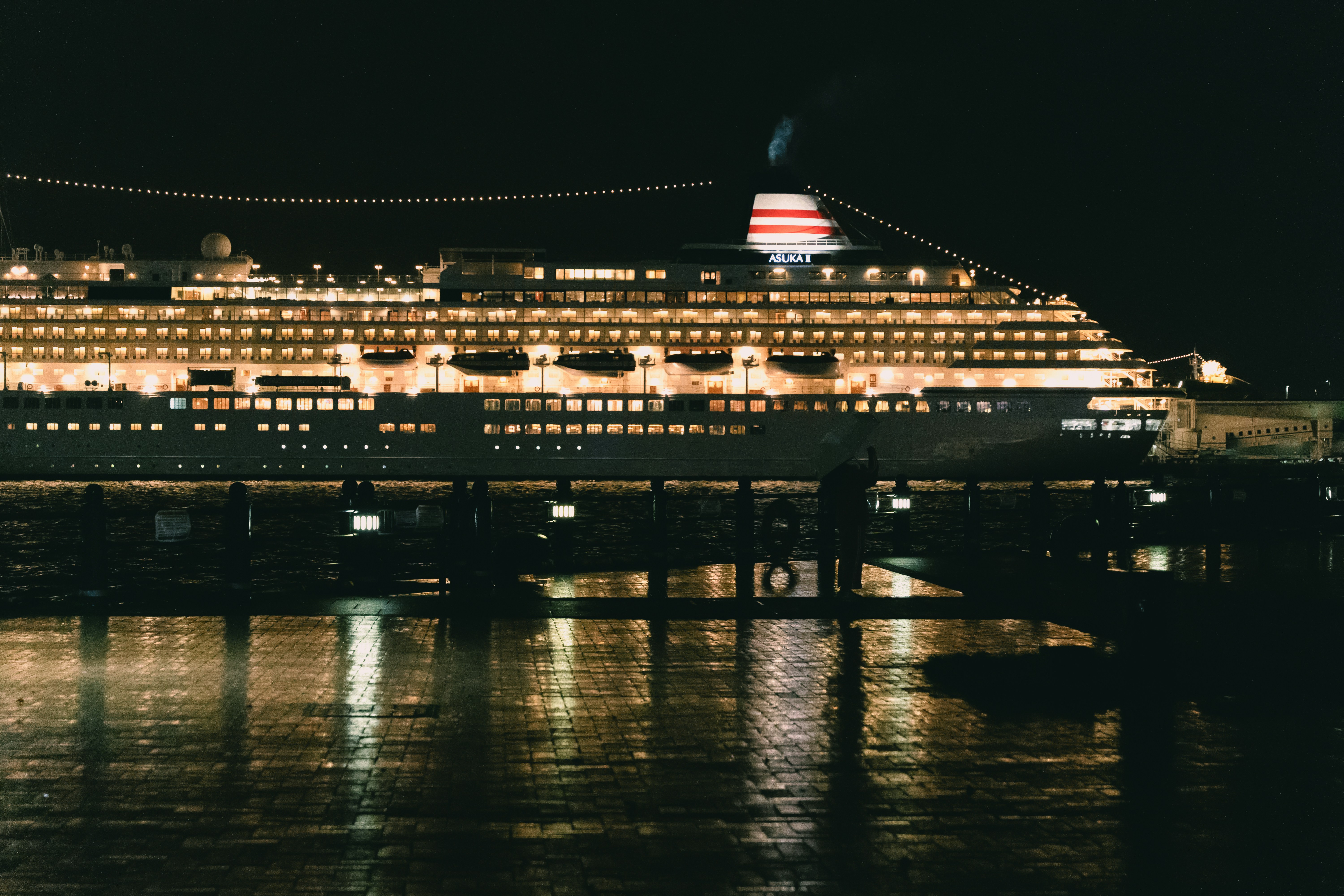 a large cruise ship docked at a pier at night