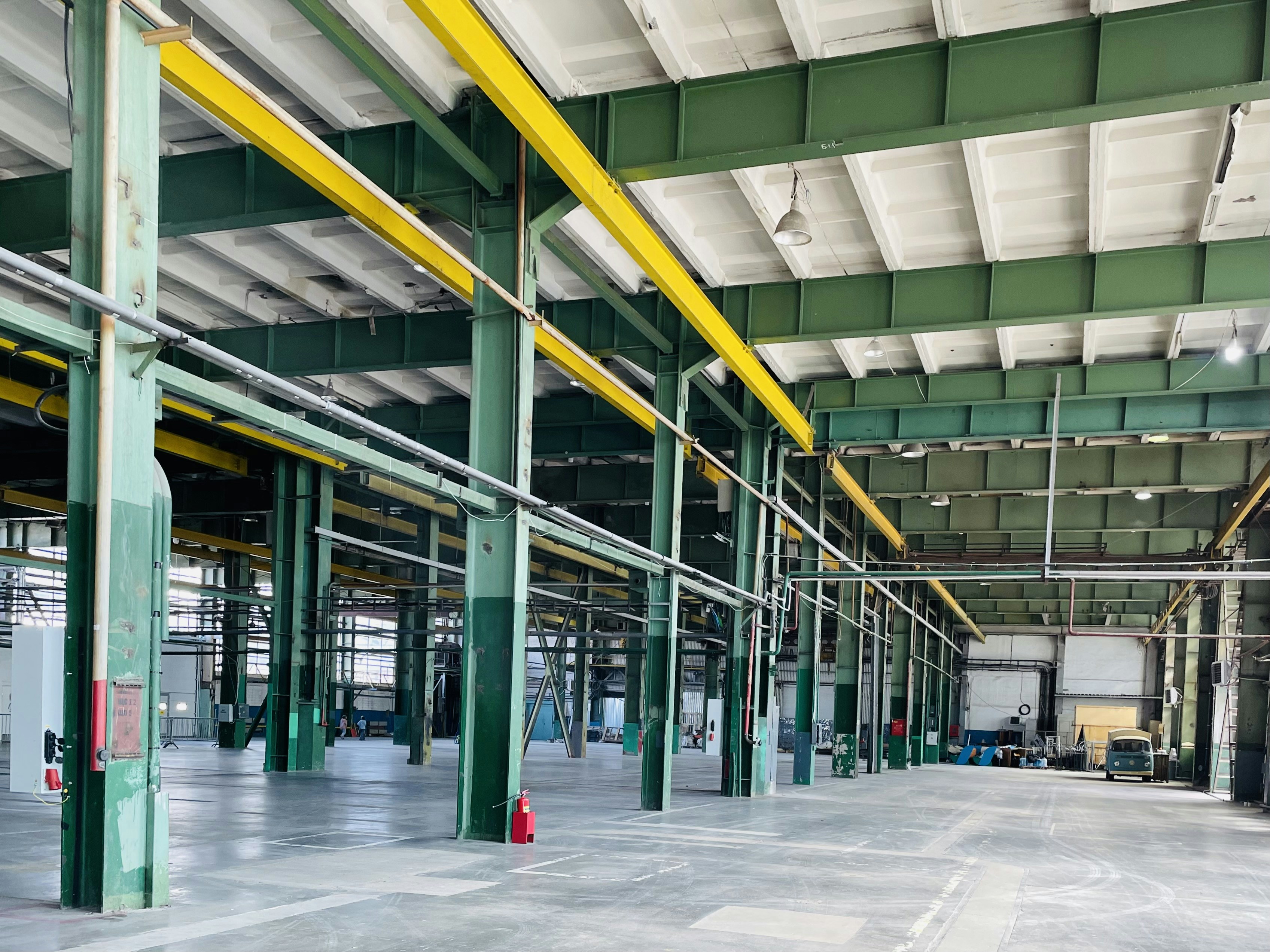 An empty warehouse with yellow and green pipes photo – Free Premises ...