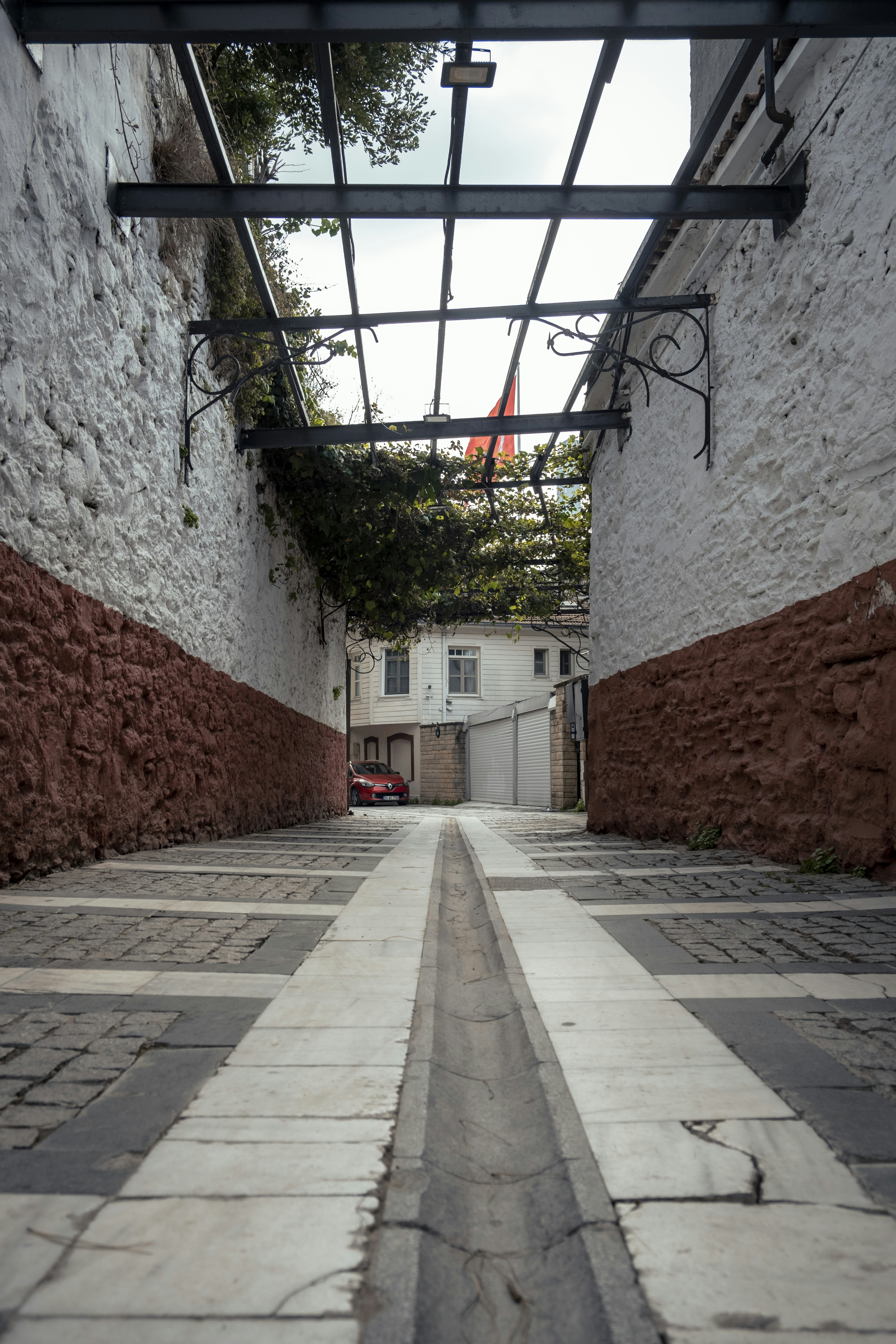 Overhead Grid, Narrow Alley, and a Red Car at the End