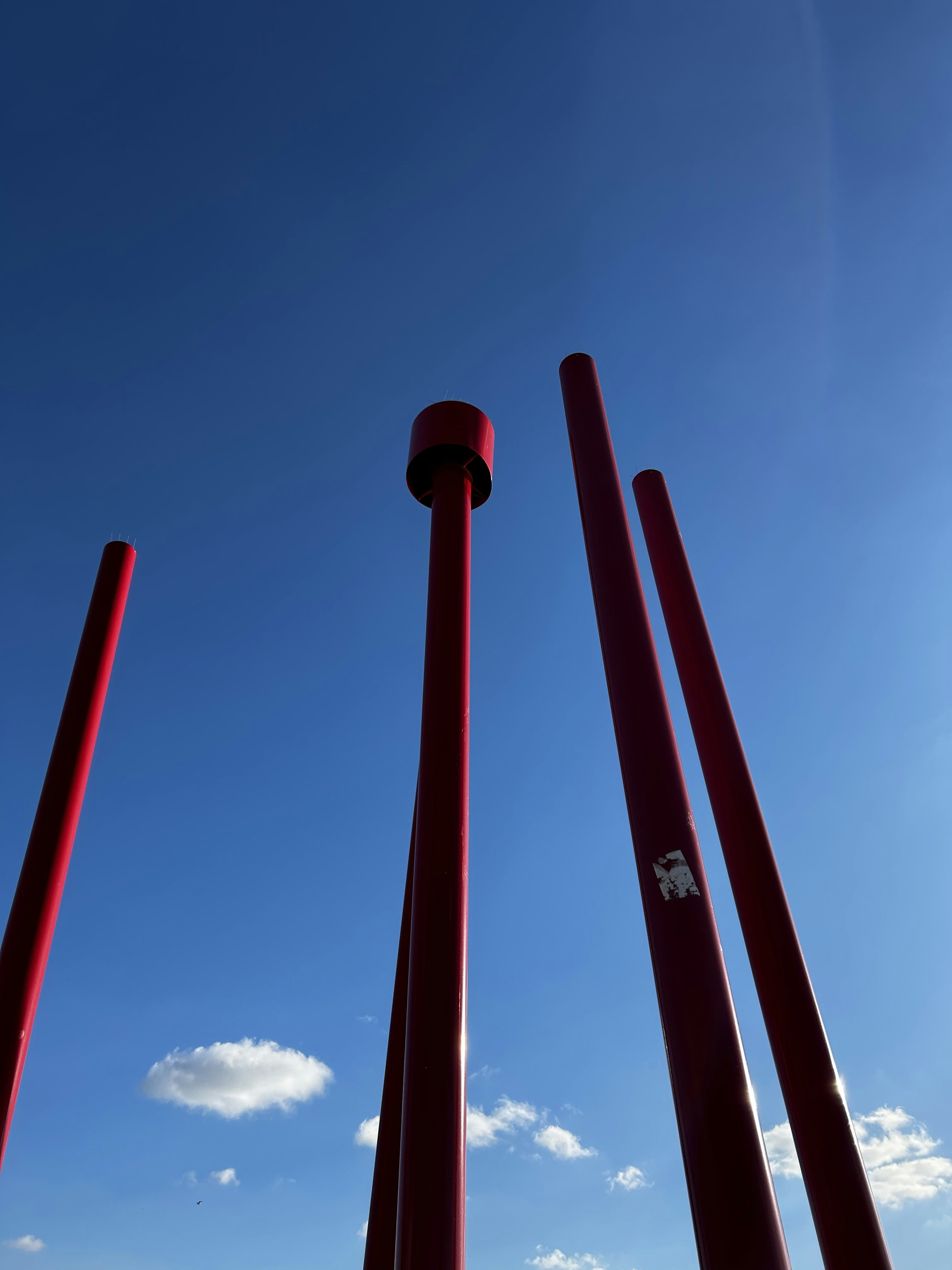 A group of red poles with a blue sky in the background photo – Free ...