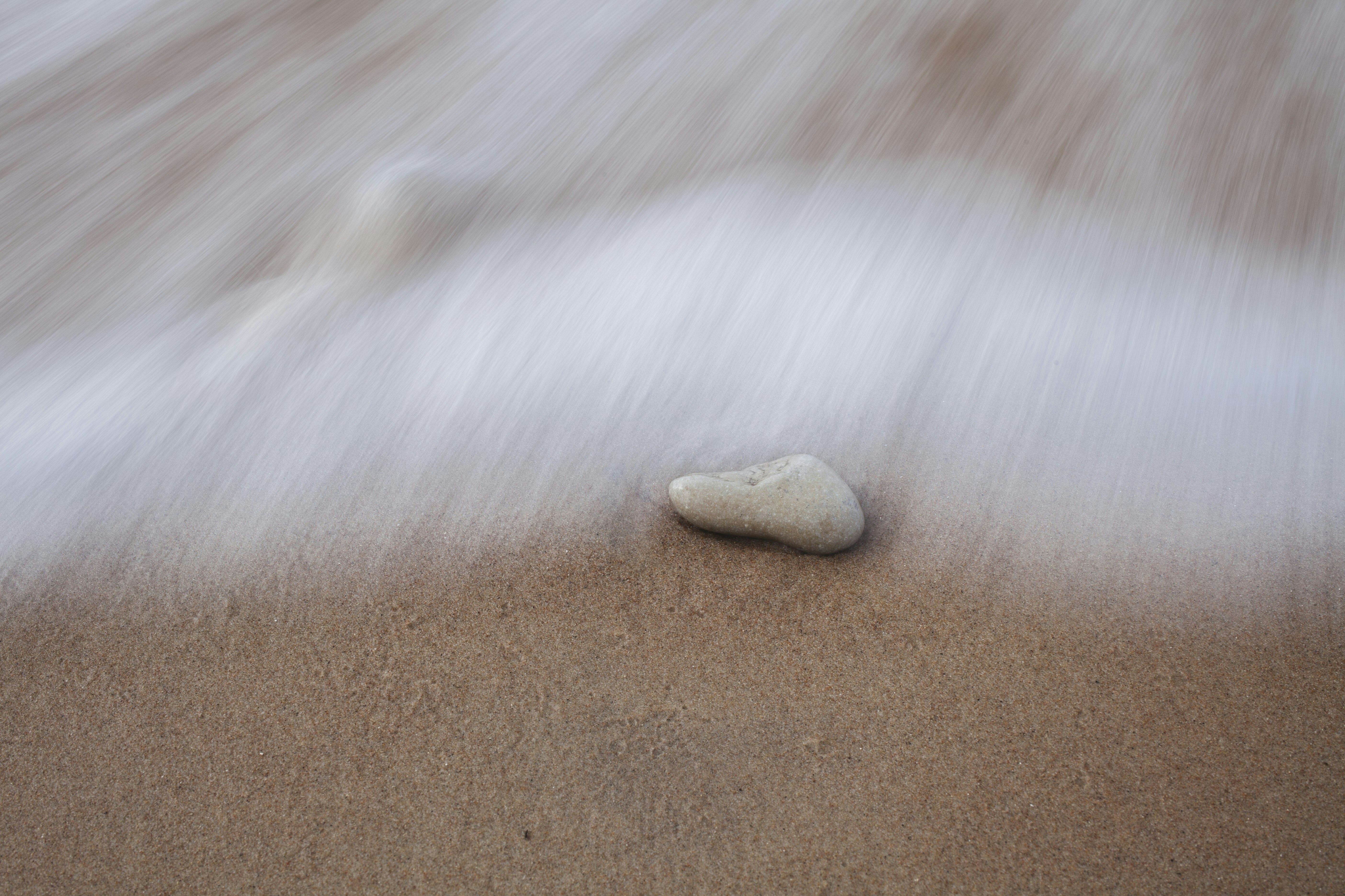Pebble on the Tide: A Gentle Moment on Wet Sand