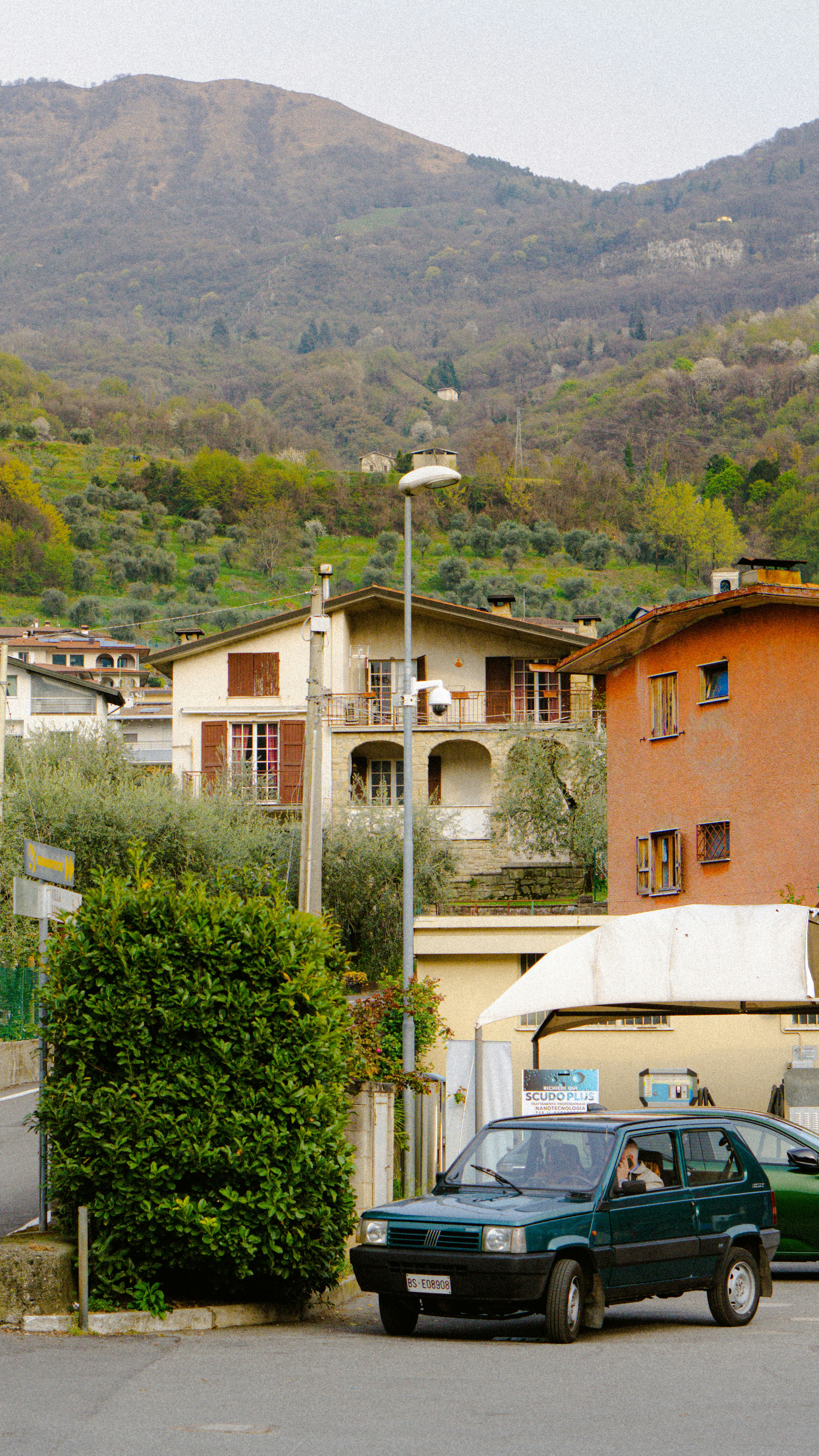 Streetlamp Vista: Green Sedan at the Edge of a Mediterranean Hillside