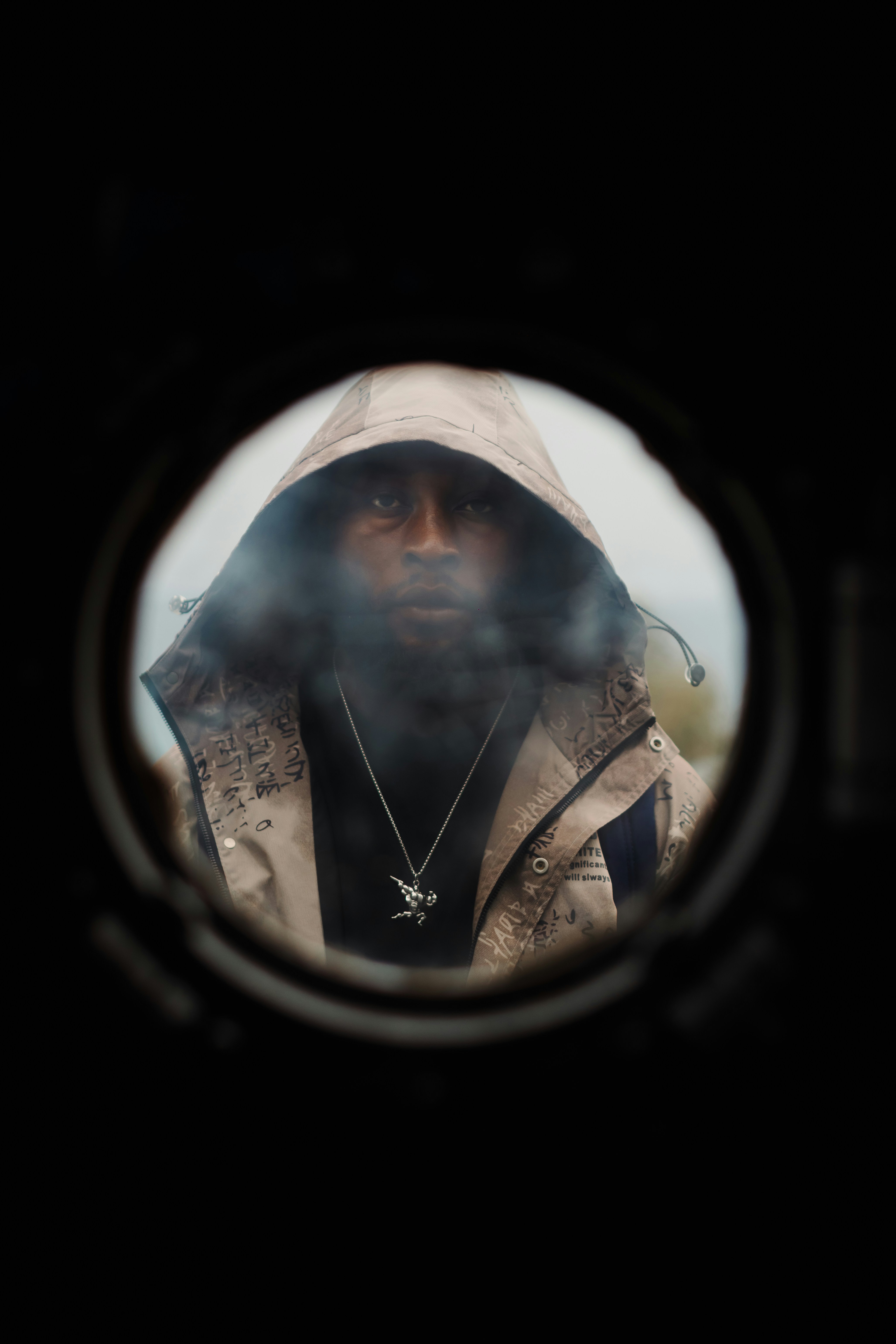 Through the Porthole: A Clad Figure Stares Back