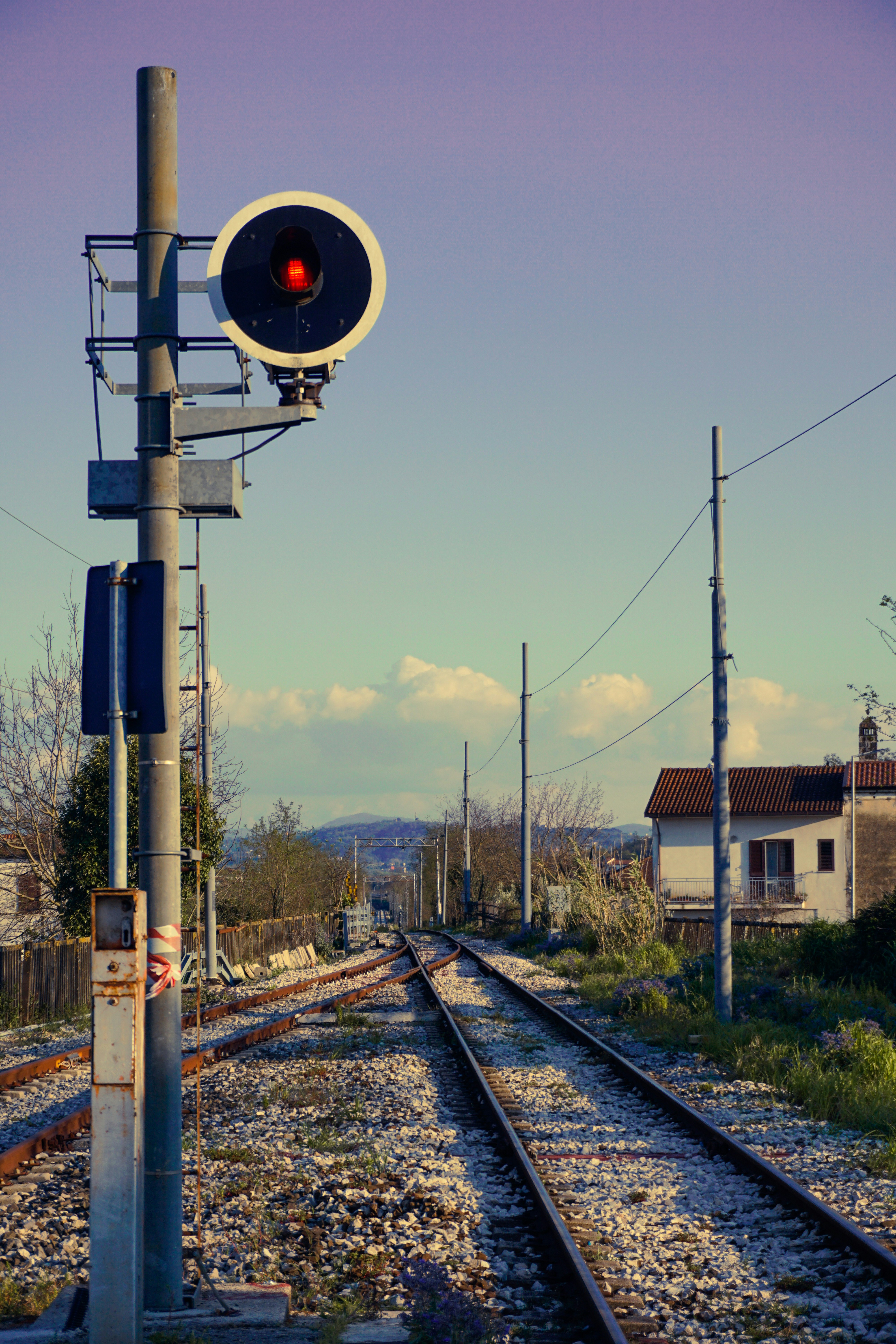 Ringed Signal at Dusk: Rails Open a Pastel-Tinted Village Corridor
