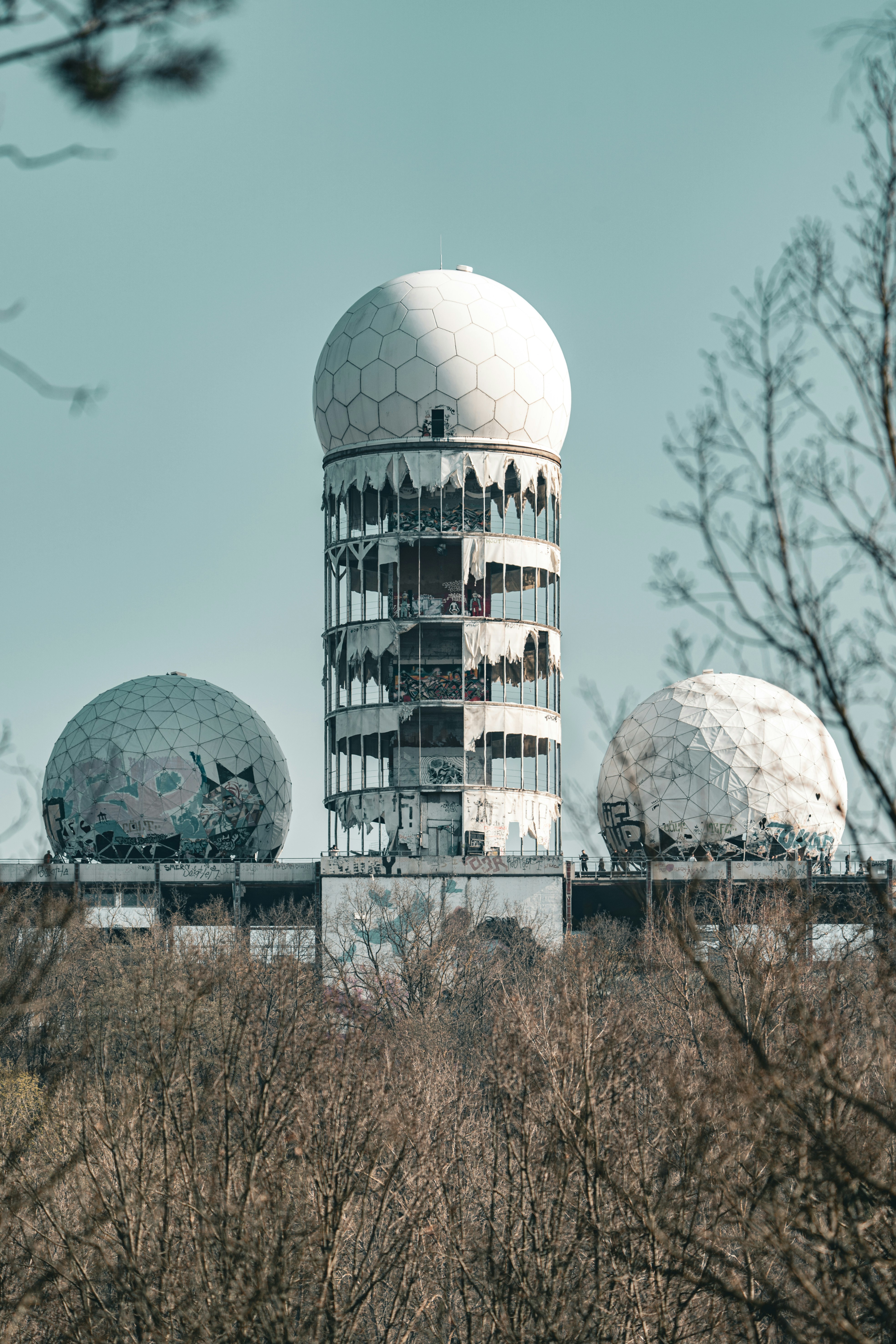 Monolithic Radar Tower Framed by Geodesic Domes in a Winter Clearing