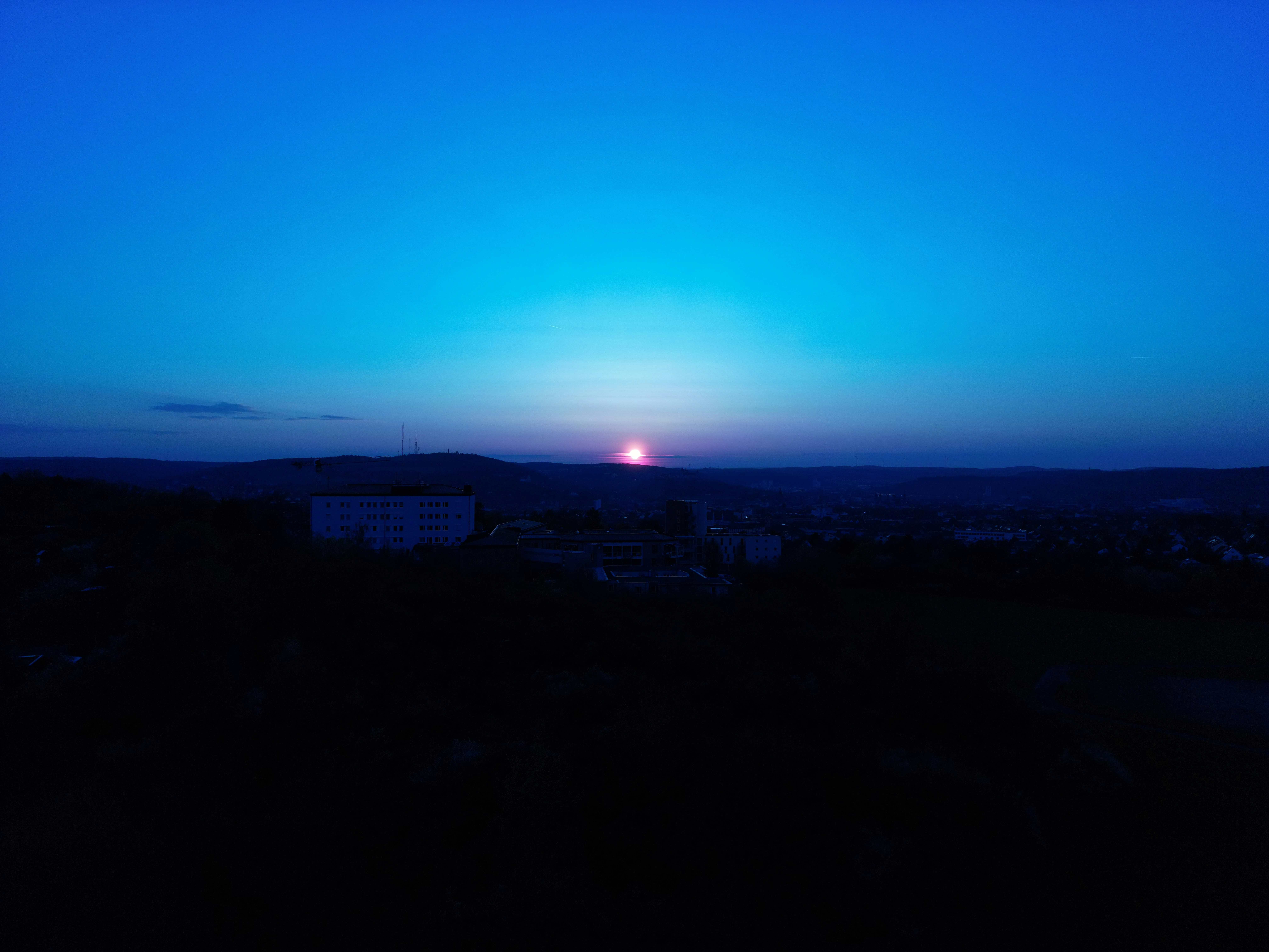 Sun setting on the horizon casting a deep blue hue over the landscape.
