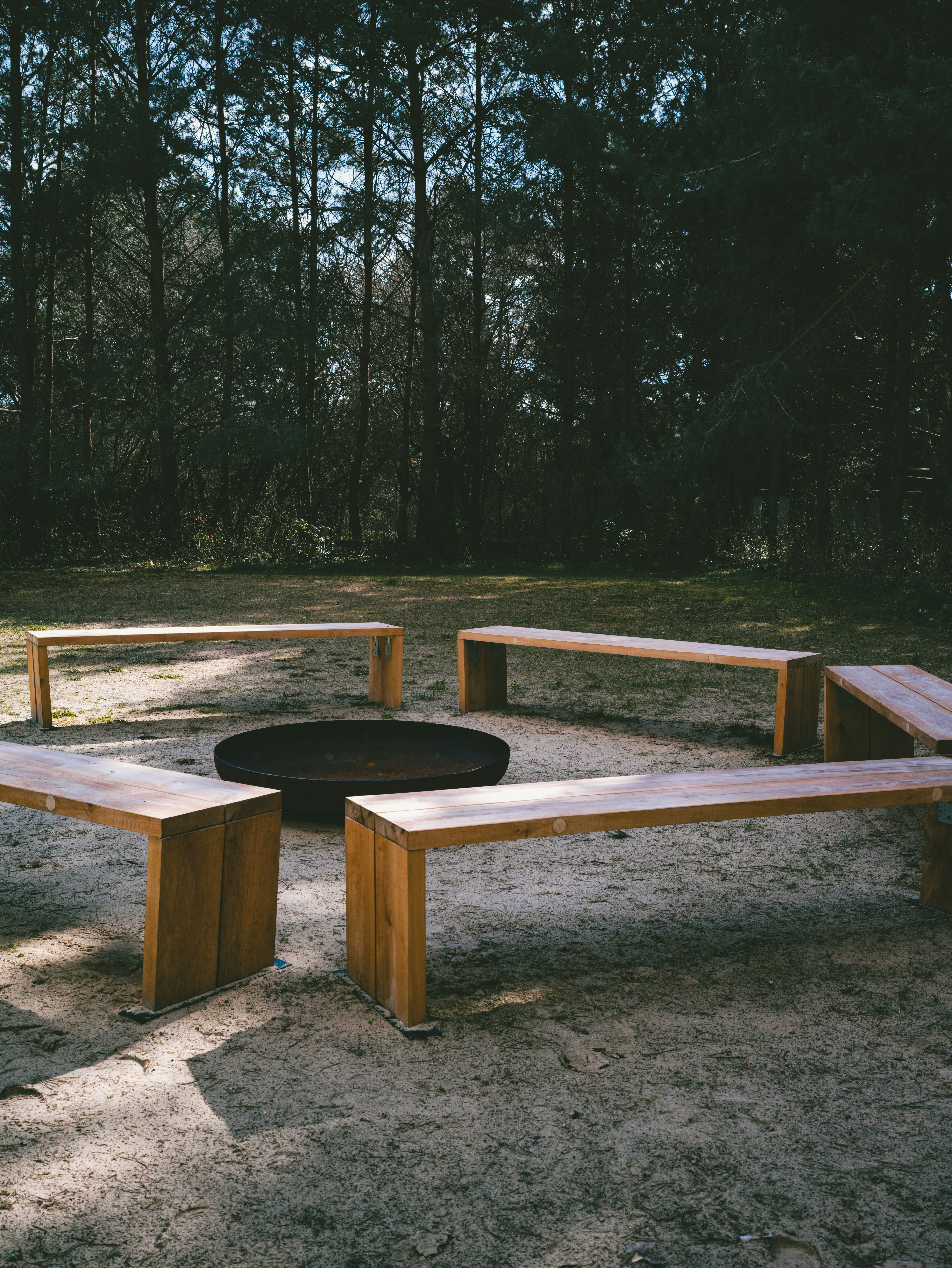 A group of wooden benches sitting next to a fire pit photo – Free ...