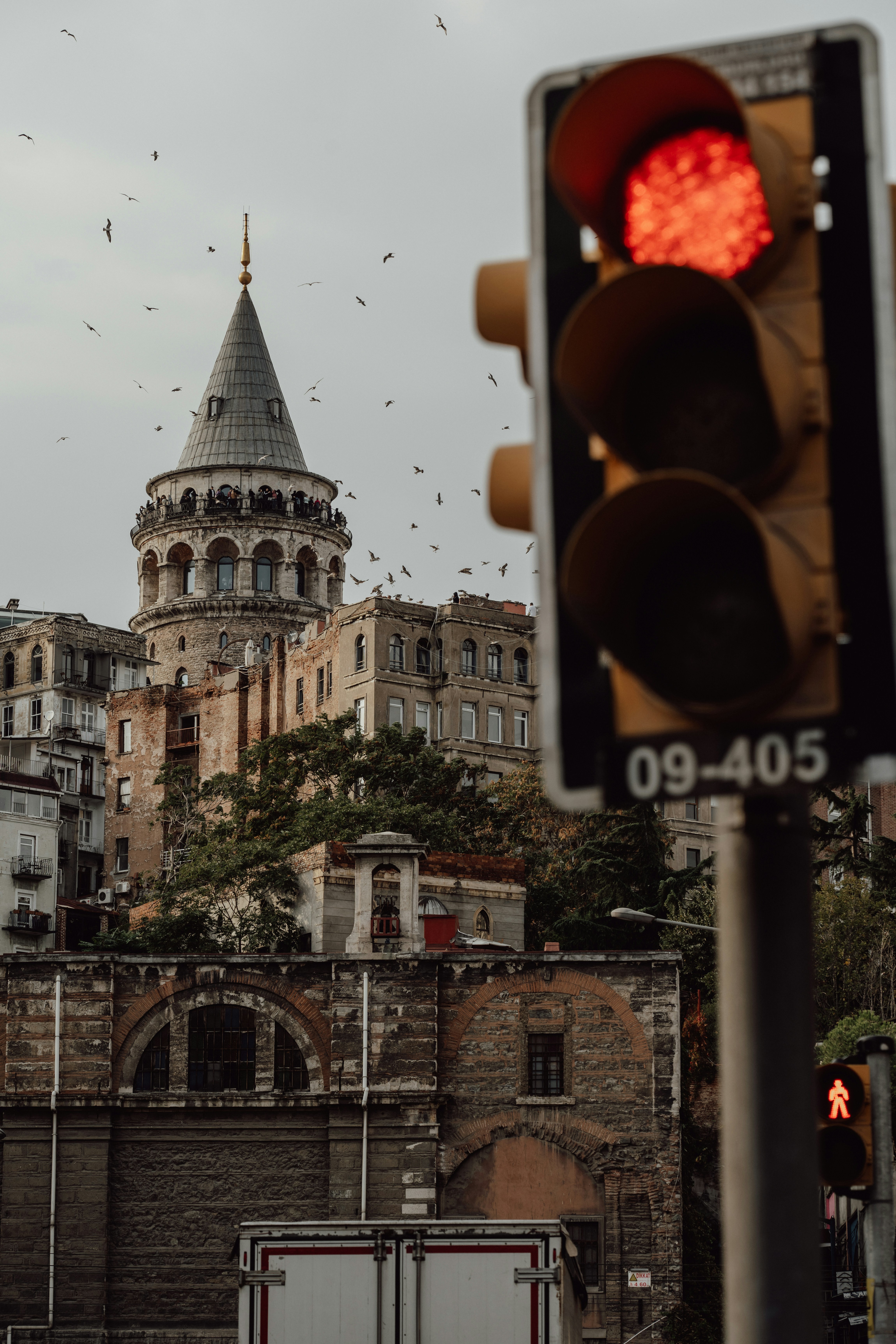 Galata Tower Amid Urban Flow: A Red Signal Framing Istanbul's Historic Skyline