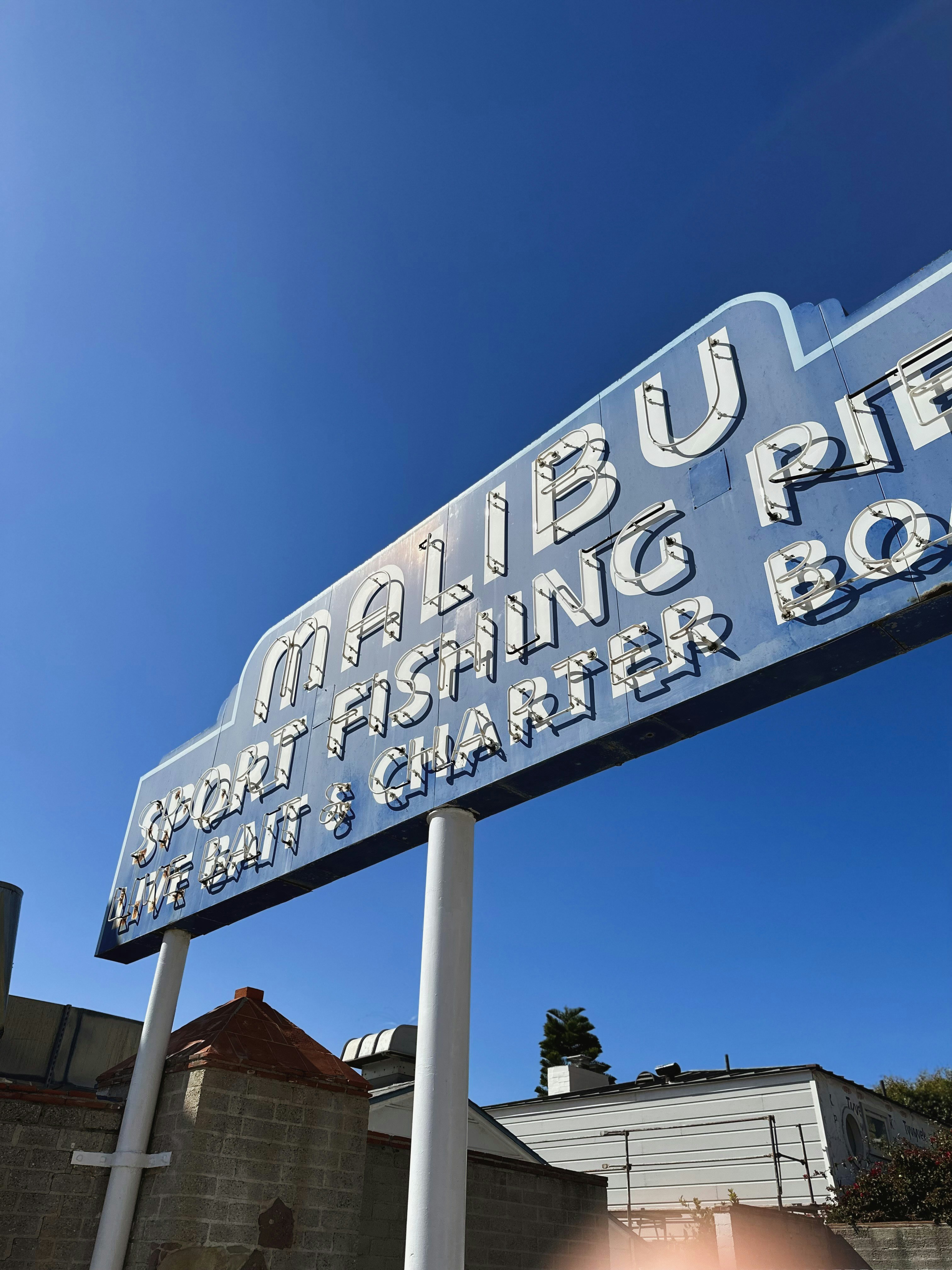 Neon Coast Sign Beneath a Clear Blue Sky