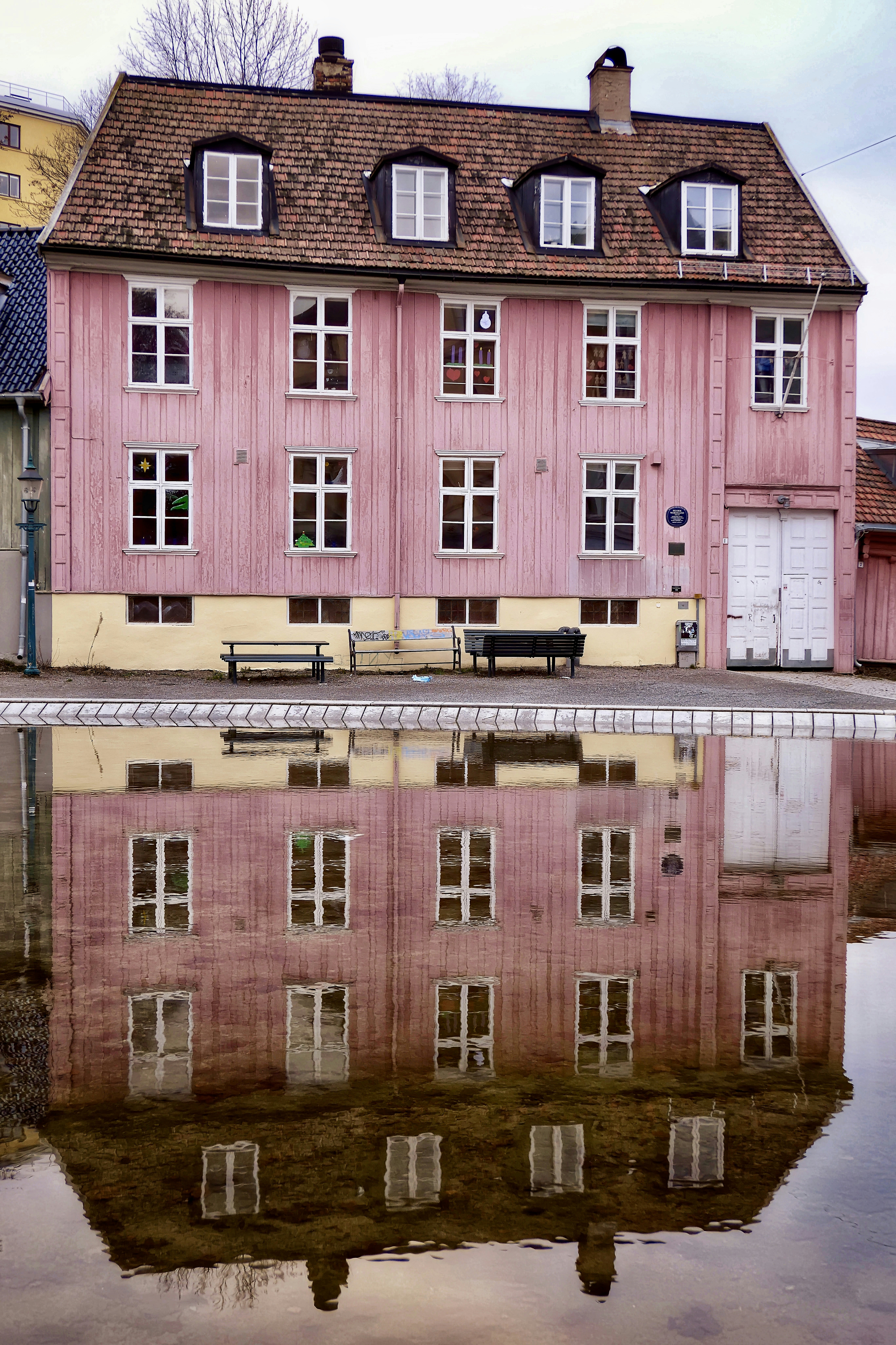 Pink Facade, Silent Mirror: A Cozy Town House Reflected in Still Waters