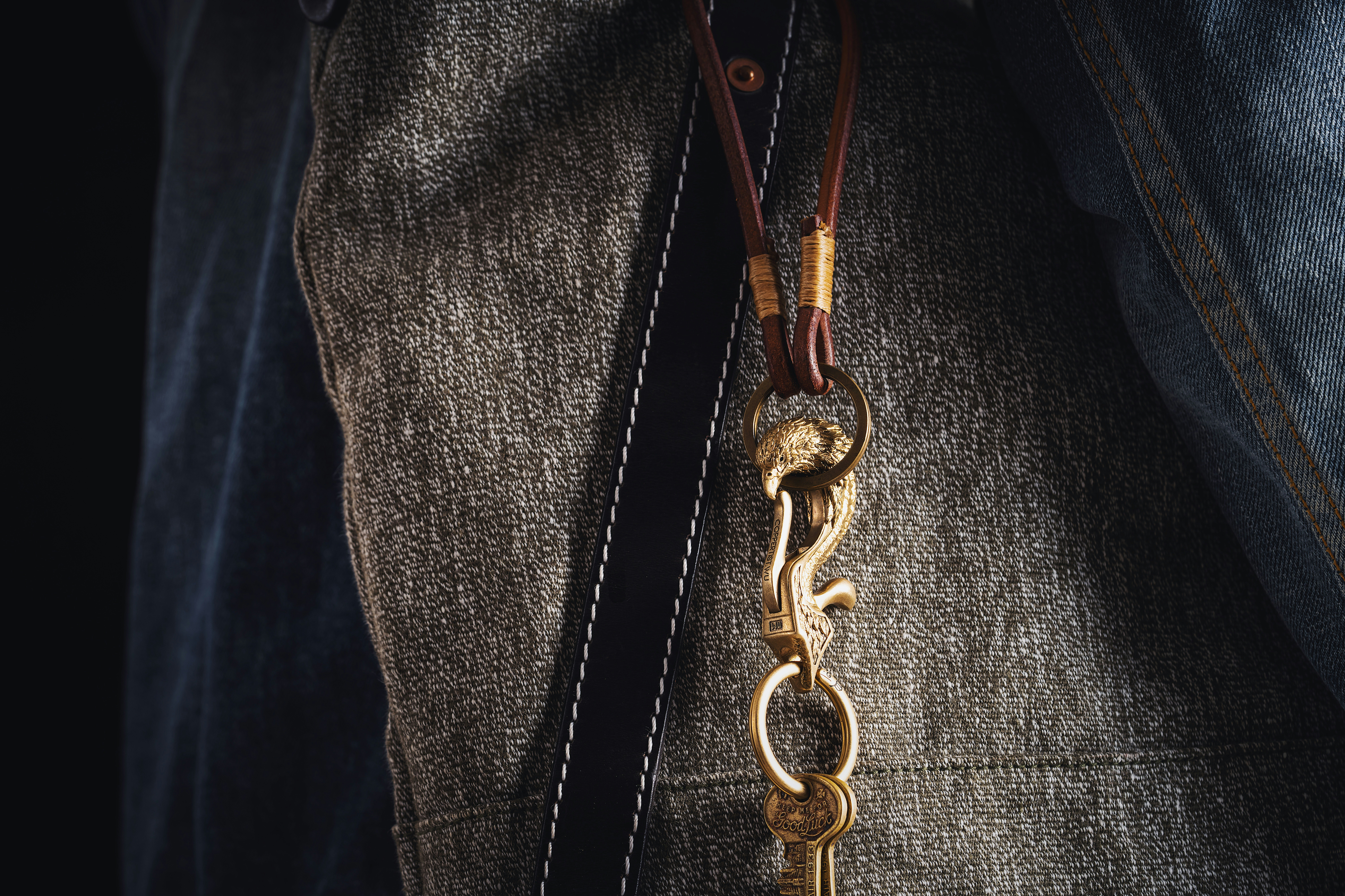 Close-up of a textured denim pocket with a brass clasp chain