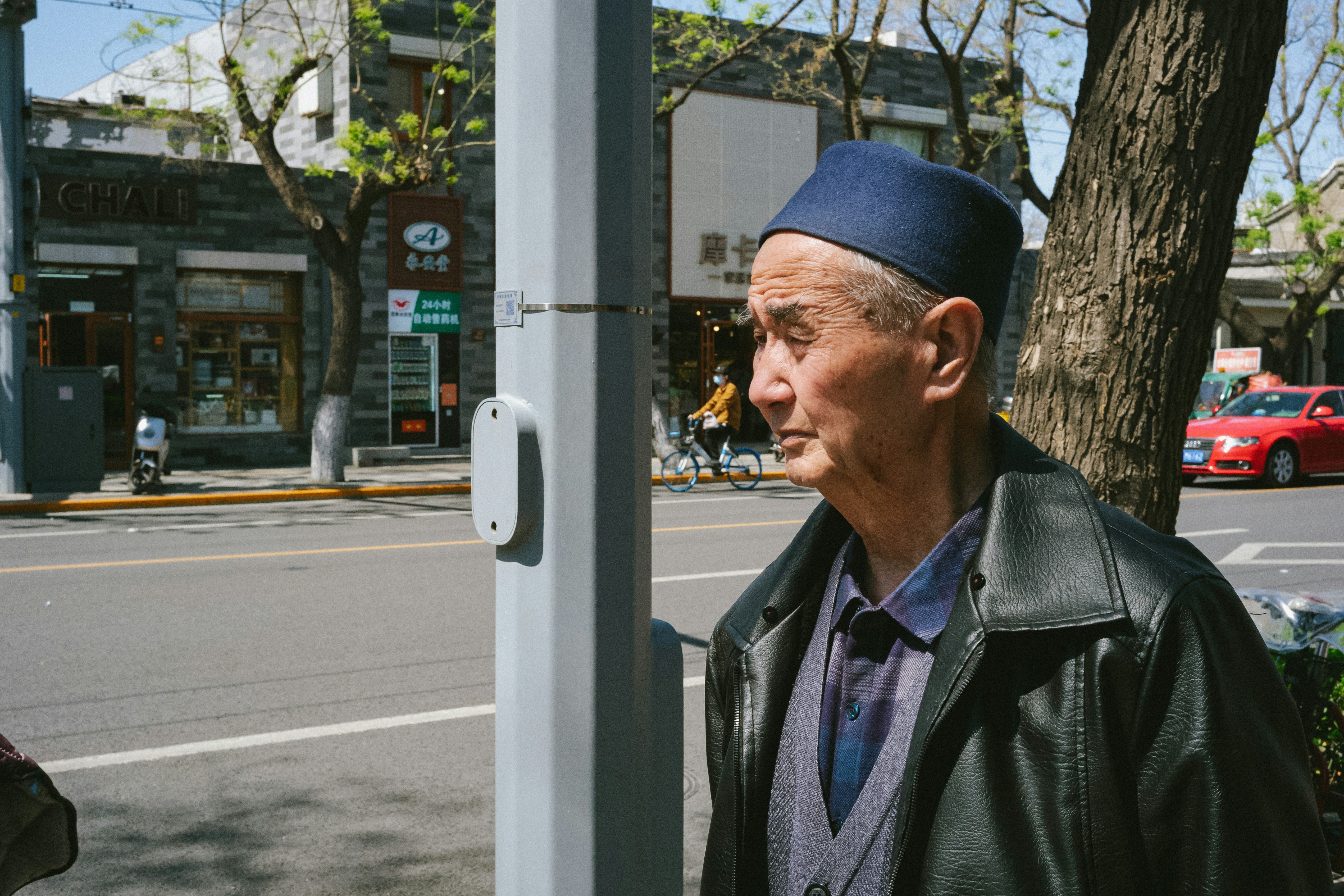 a man standing next to a pole on a city street