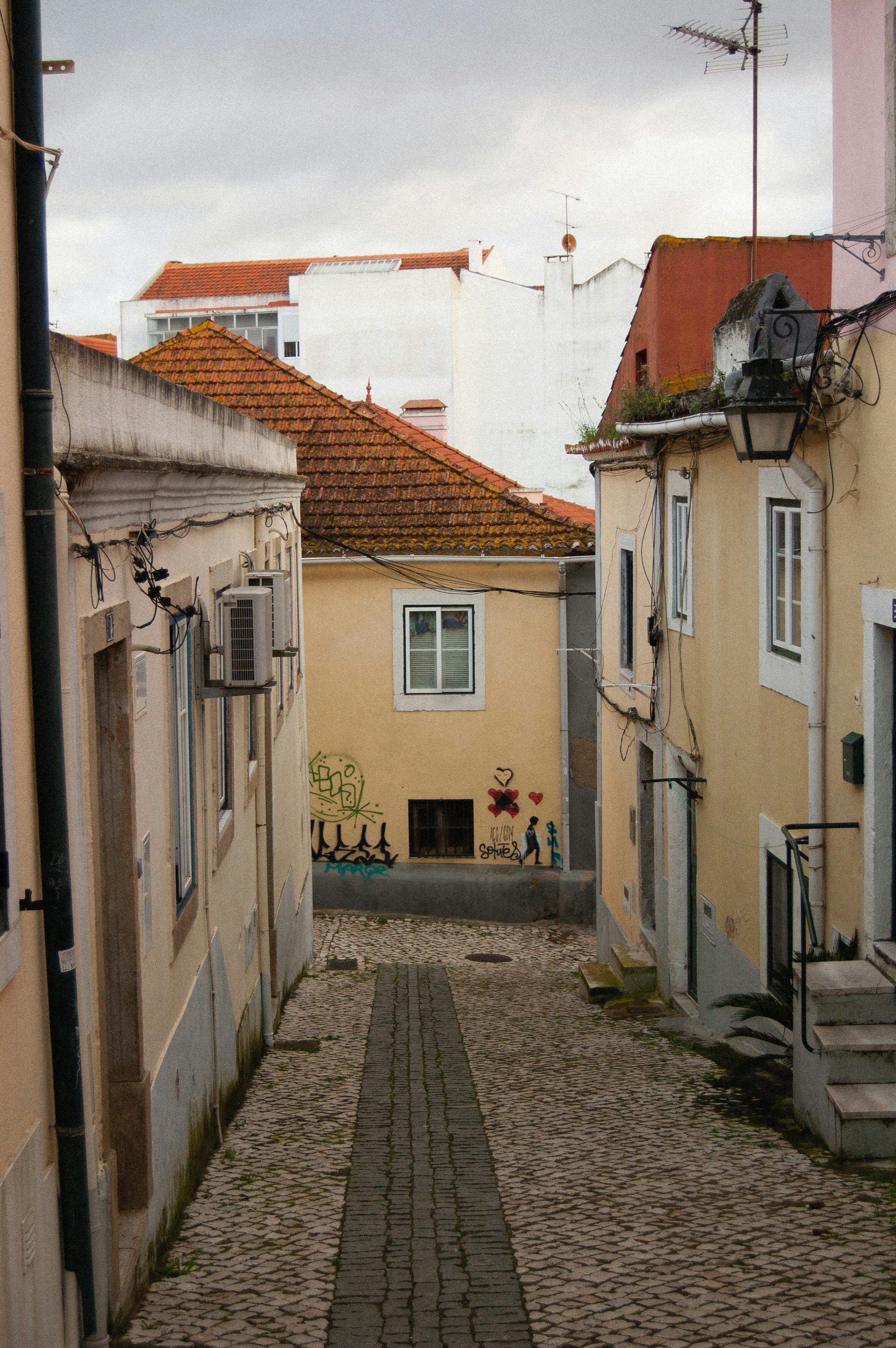 a cobblestone street with buildings and a clock tower in the distance