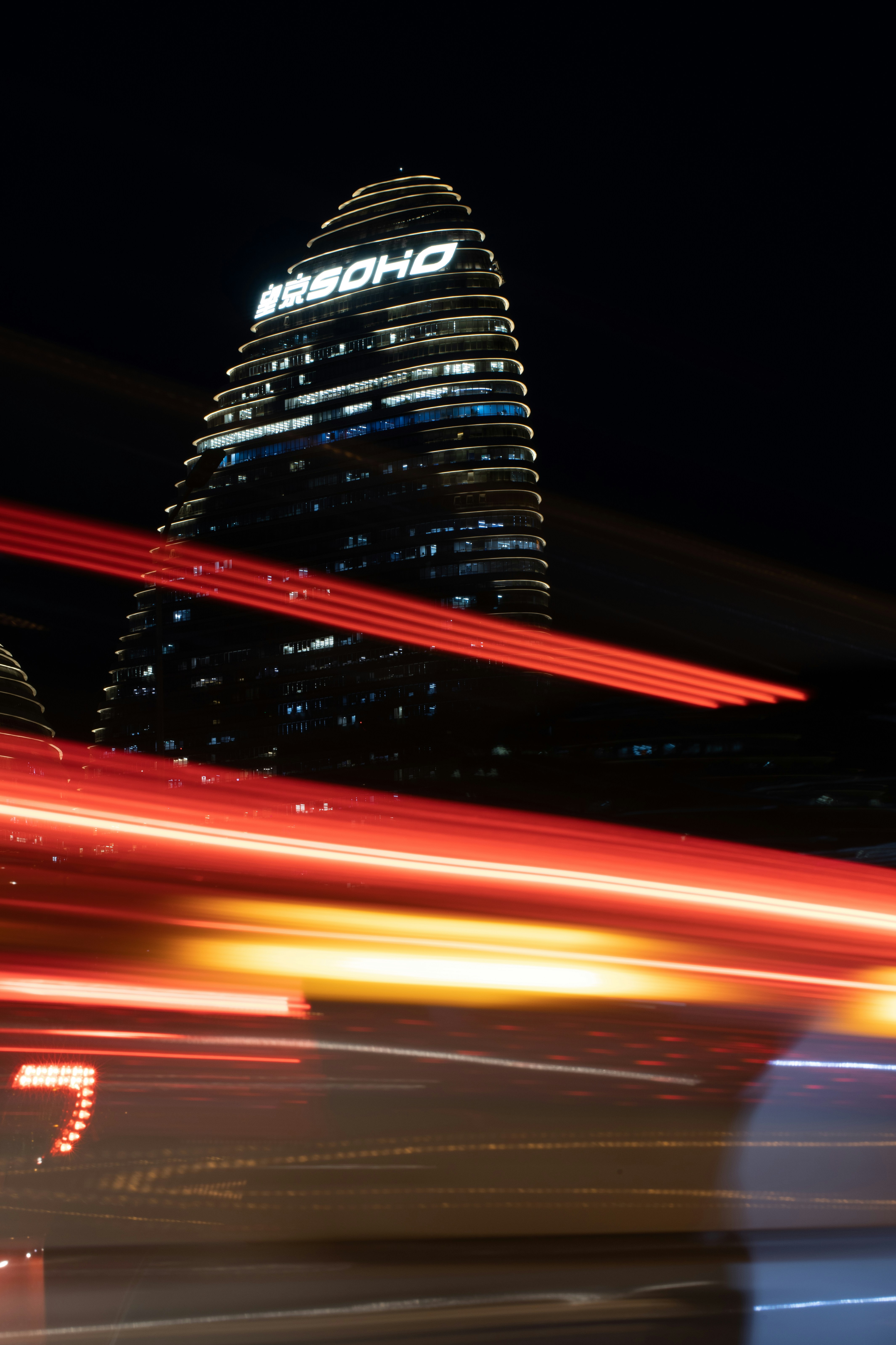 Neon Rings Over Traffic Rivers: Night Portrait of a Circular Tower