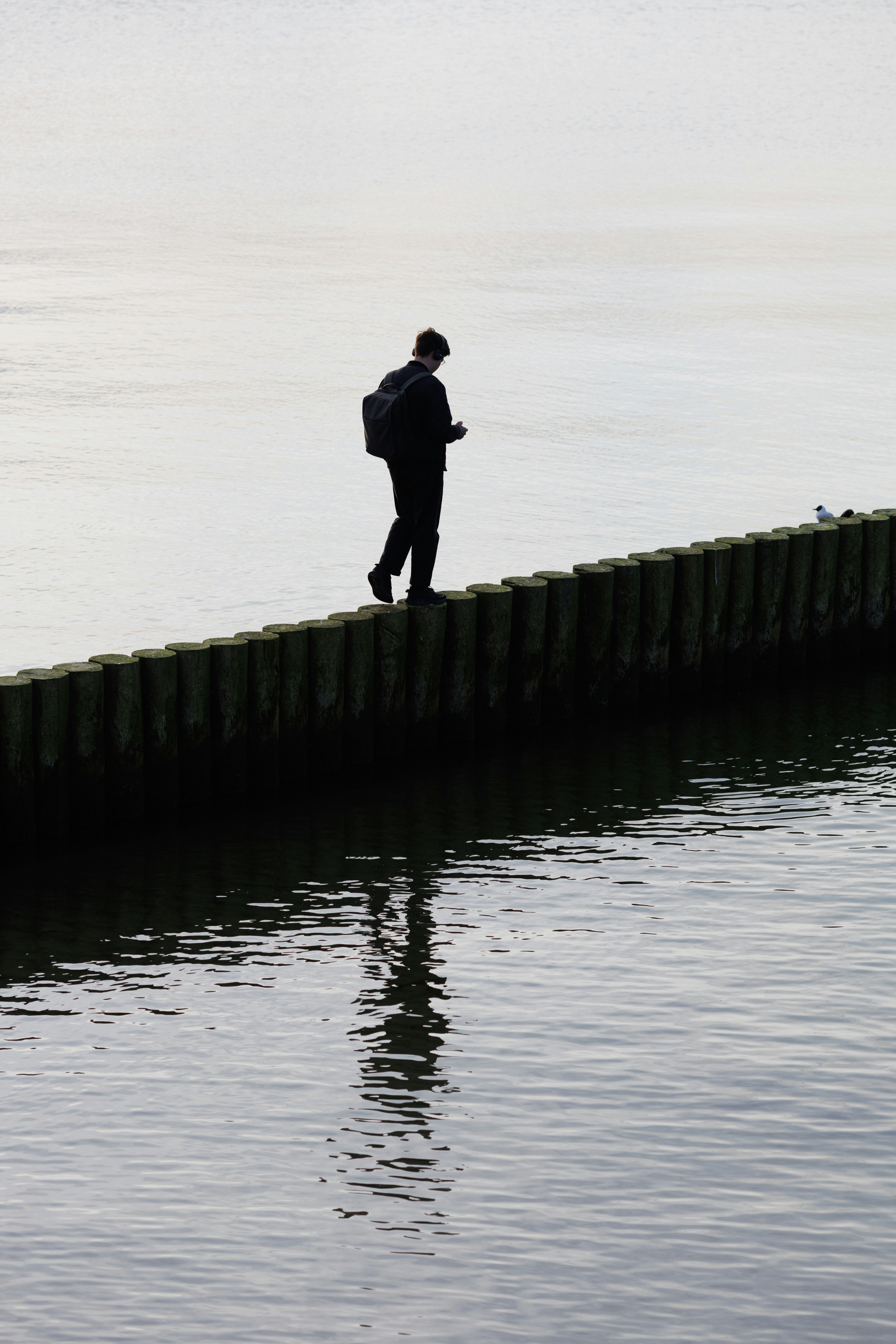 Silhouette on the Pier: A Solo Walk Along Weathered Beams