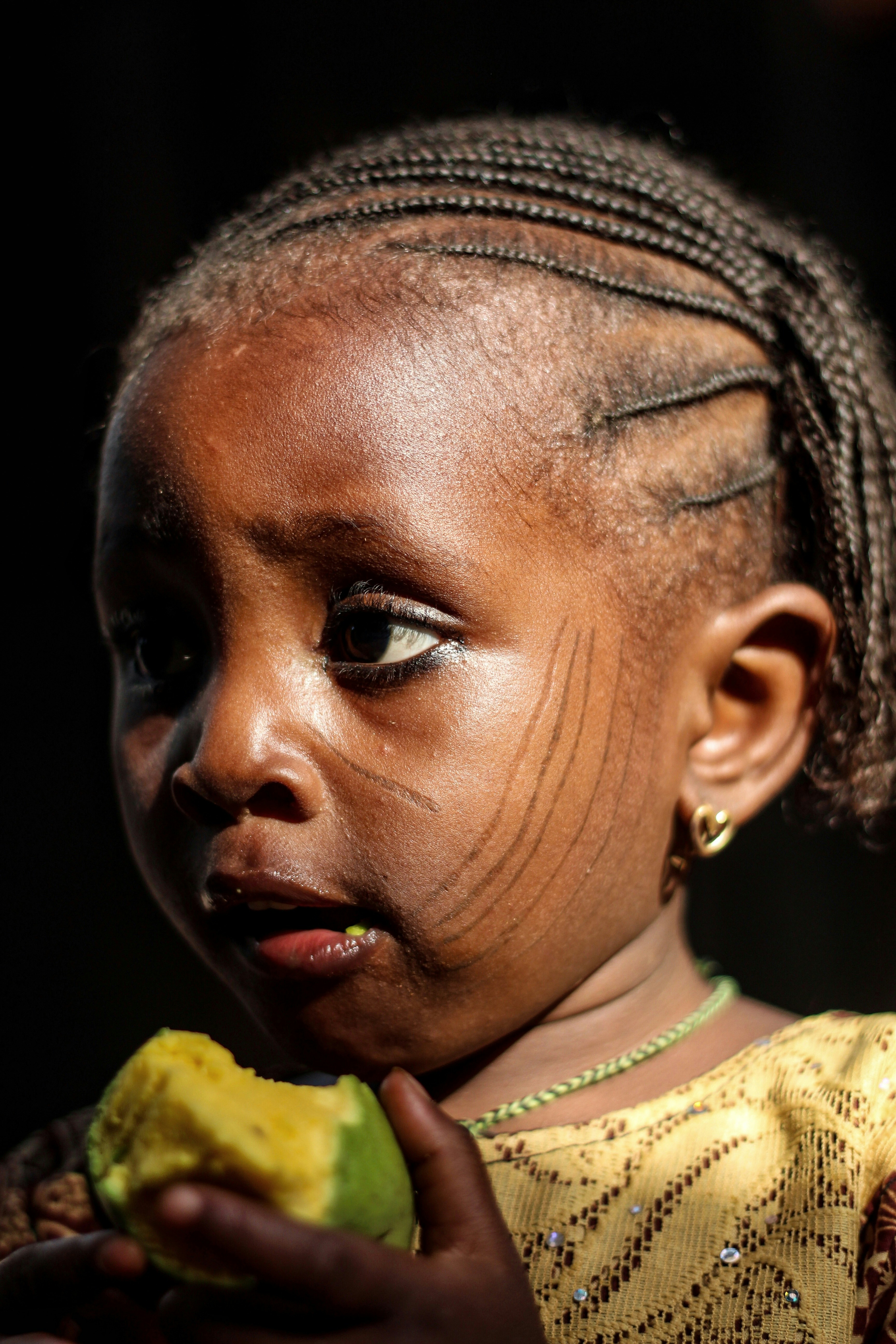 a little girl eating a piece of fruit