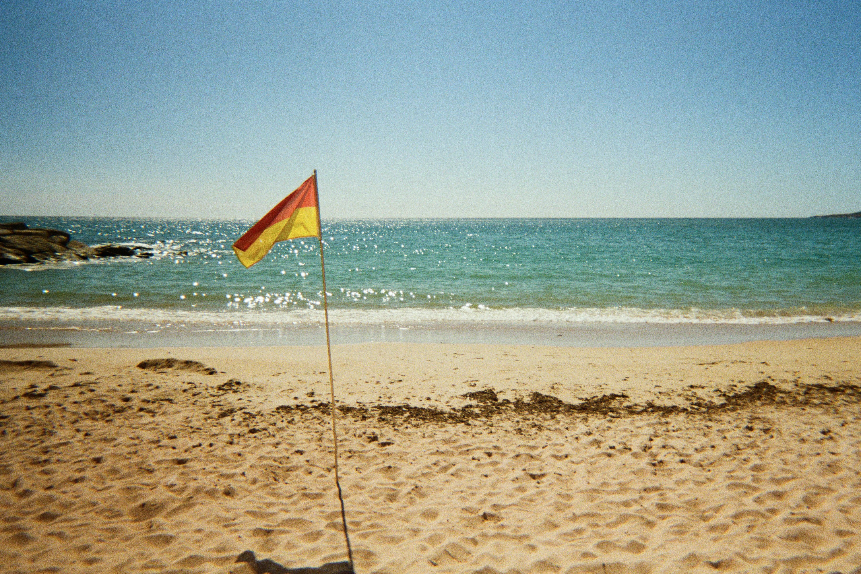 A flag sticking out of the sand on a beach photo – Free Beach Image on ...