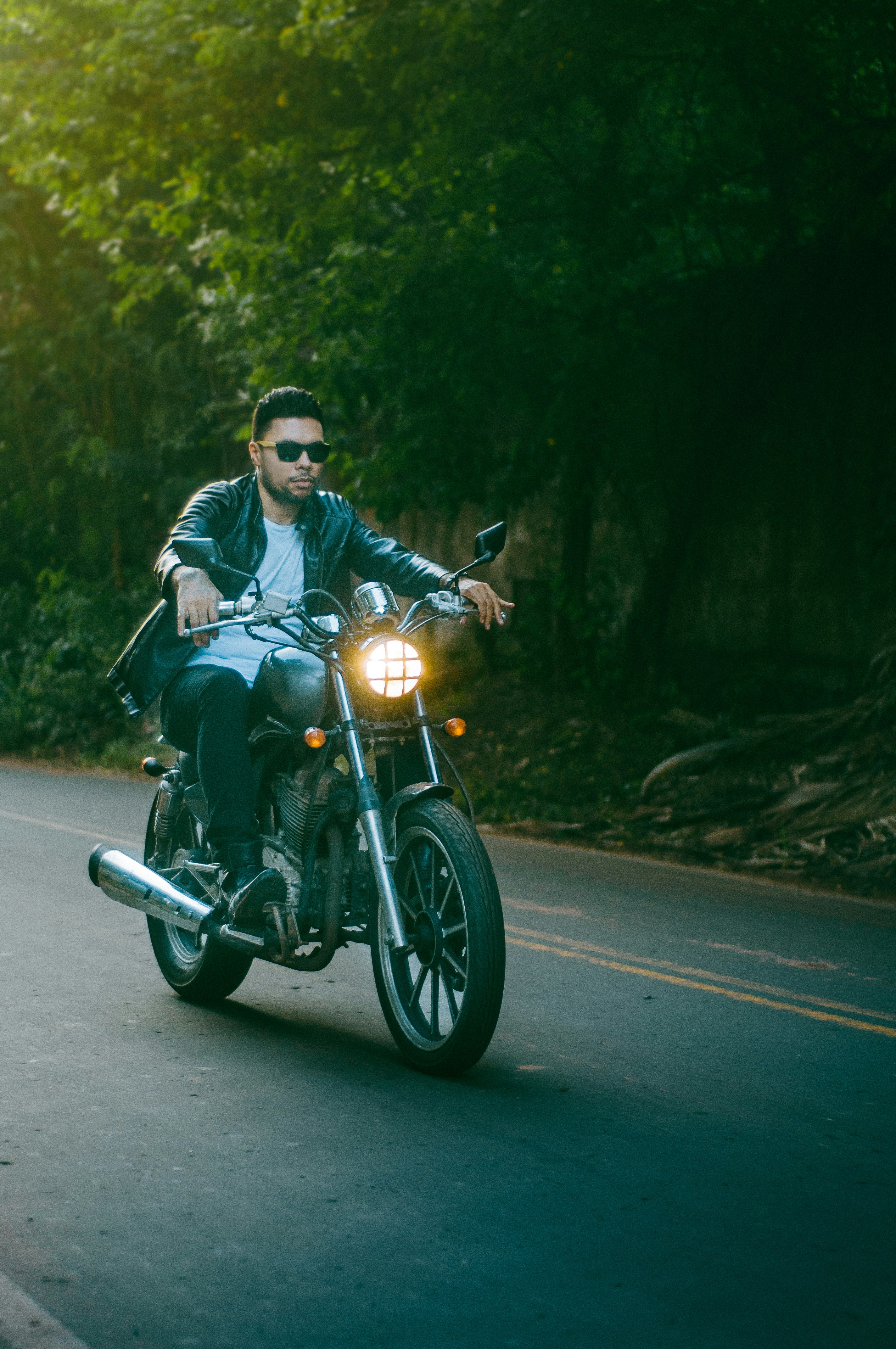 A man riding on the back of a motorcycle down a road photo – Free ...